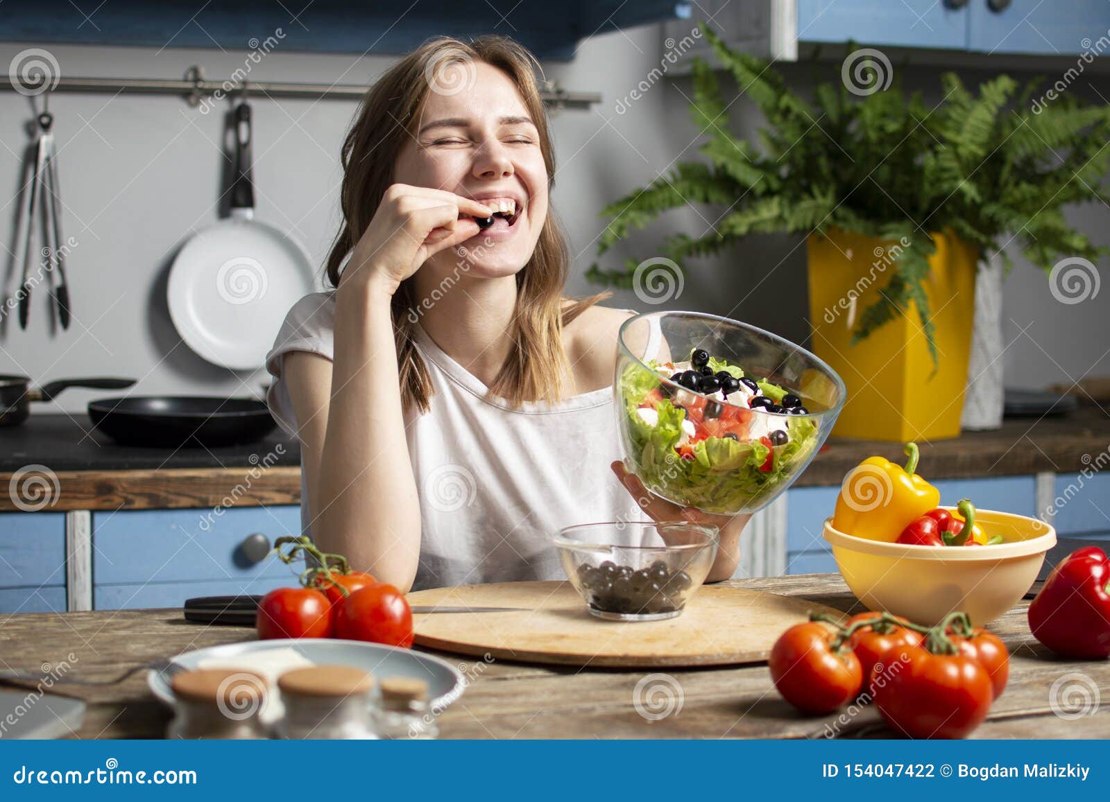 Young Girl Prepares A Vegetarian Salad In The Kitchen She Tastes Olive