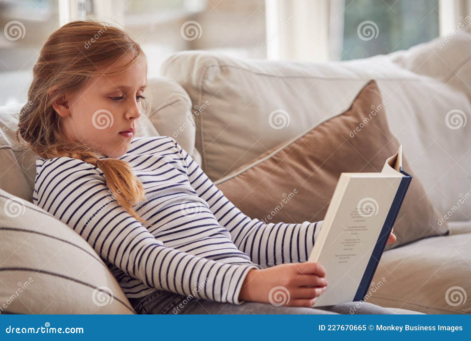 Young Girl Relaxing on Sofa at Home Reading Book Stock Image - Image of ...