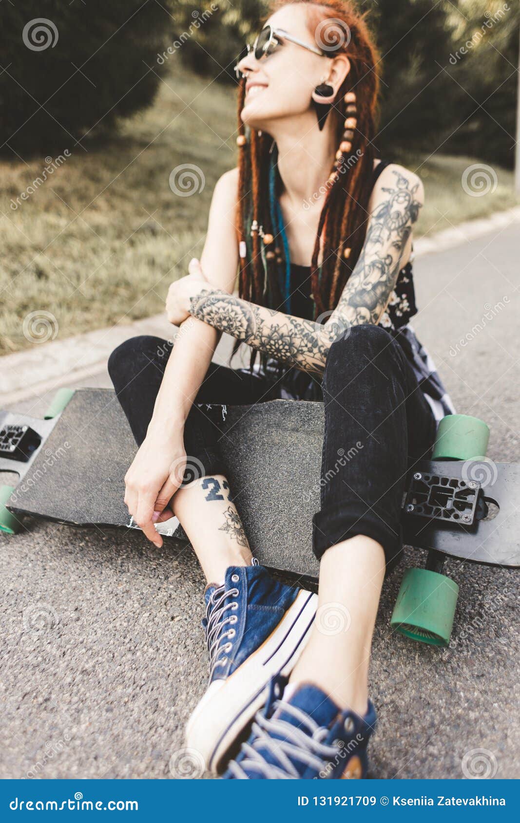 Young Girl With Tattoo And Dreadlocks Sitting In The Park Stock Image