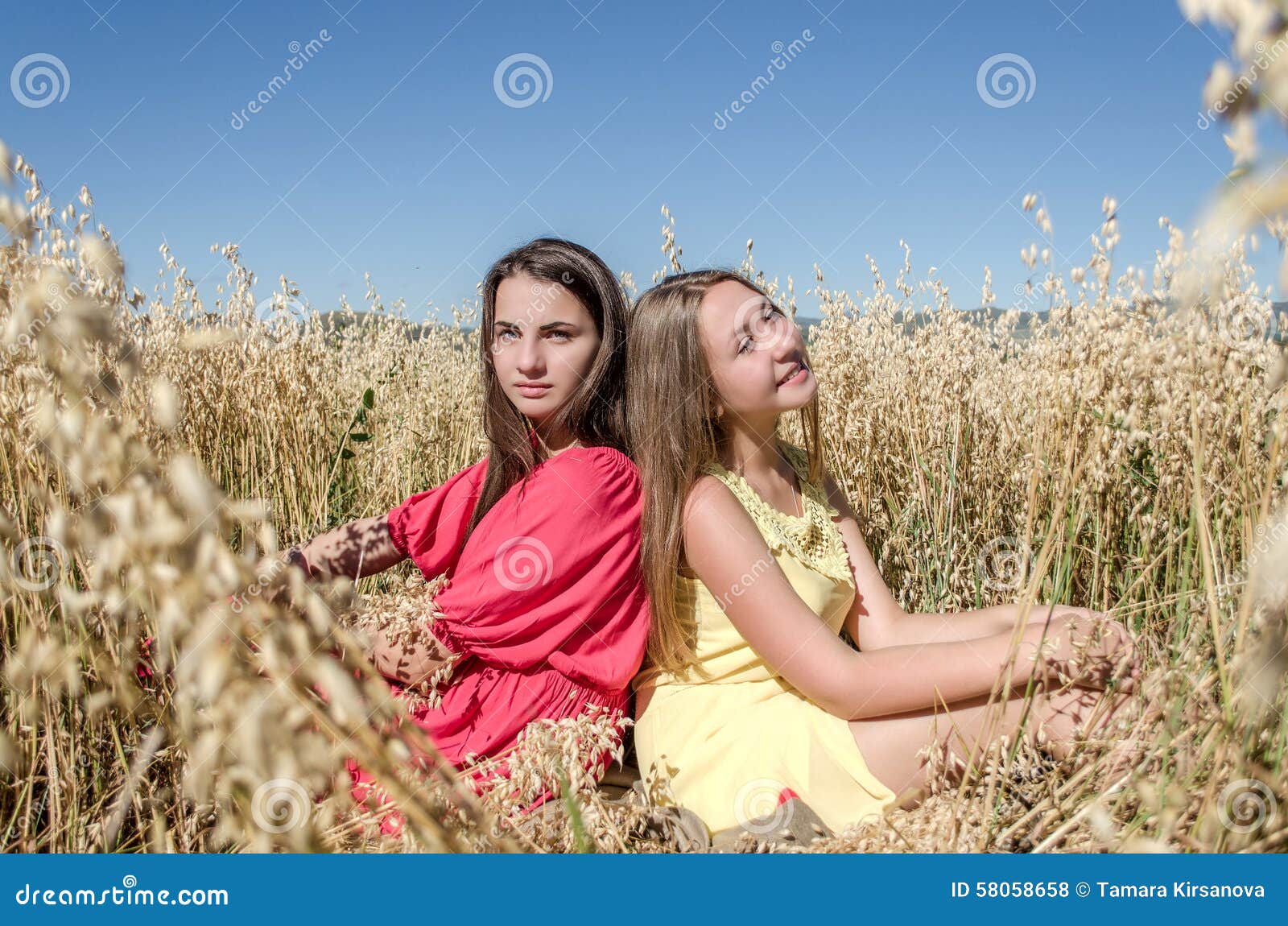 Young Girls Sitting in a Field in the Sun Stock Photo - Image of smile ...