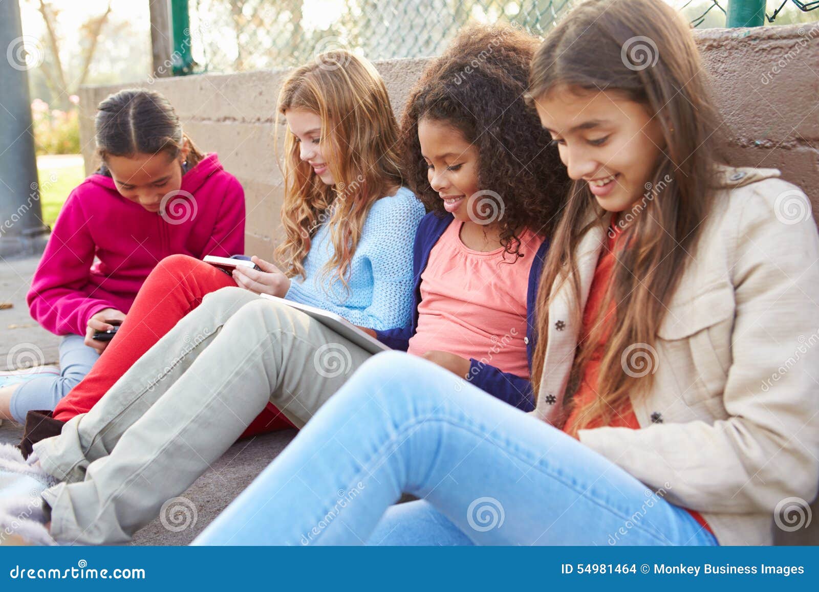 Young Girls Using Digital Tablets and Mobile Phones in Park Stock Photo ...