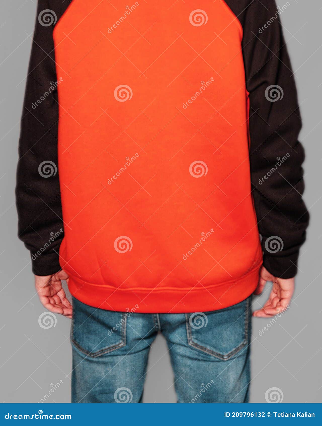 A Young Guy Dressed in a Orange and Black Hoodie Standing Backwards ...