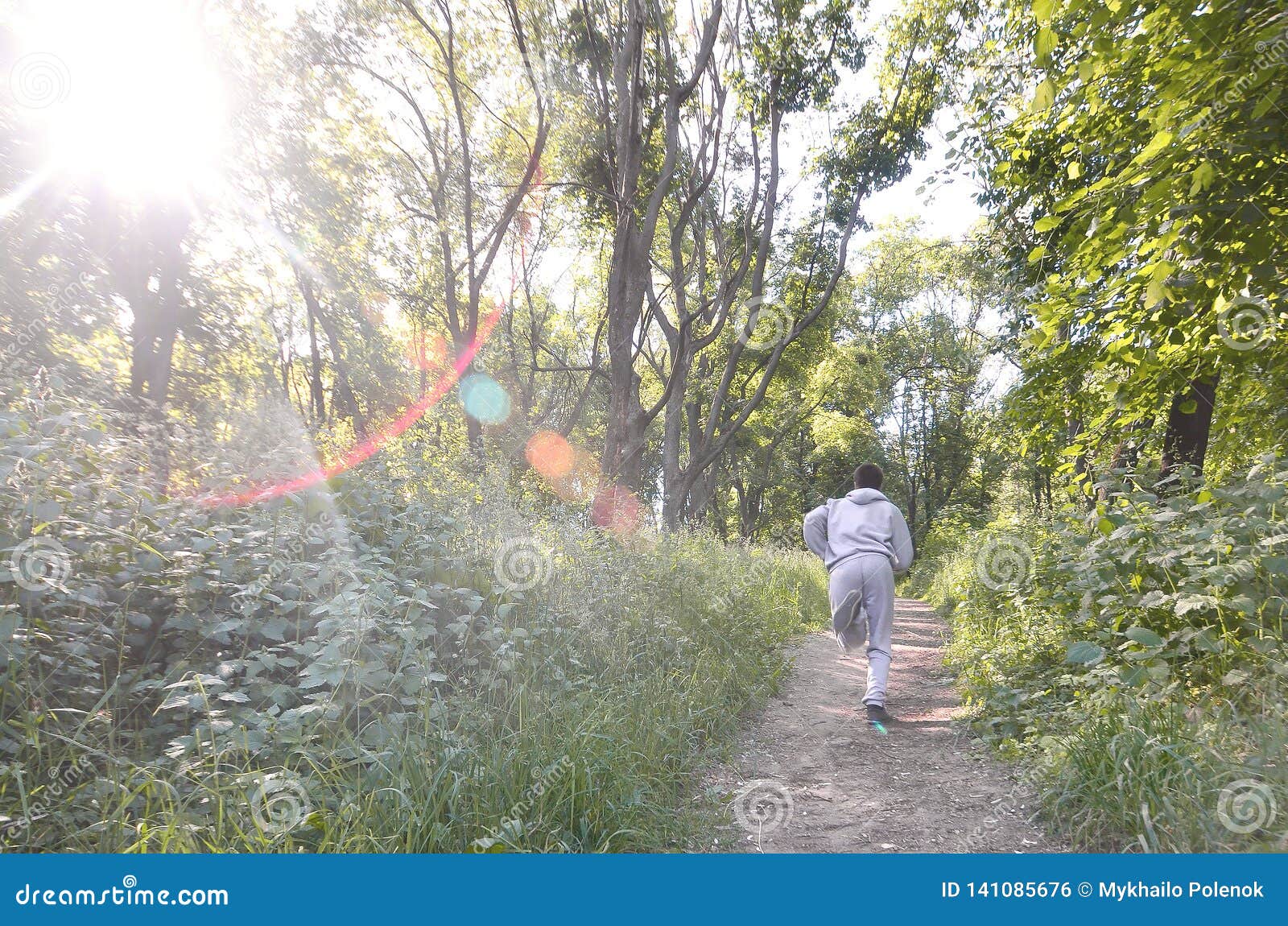 A Young Guy in a Gray Sports Suit Runs Along the Path among the Stock ...