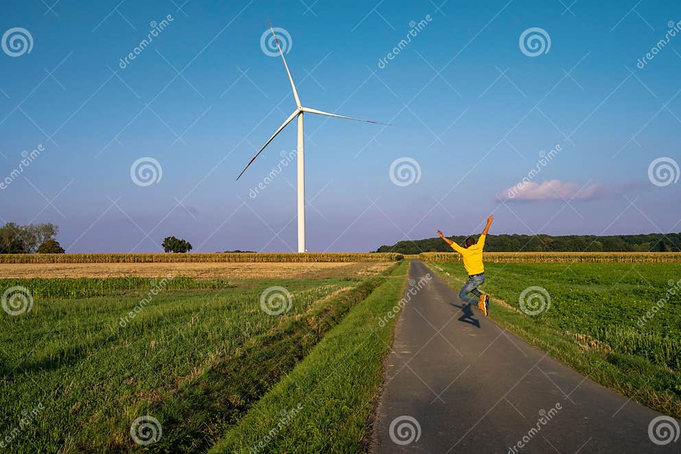 Young Guy Jumping in from of a Wind Turbine Stock Image - Image of ...