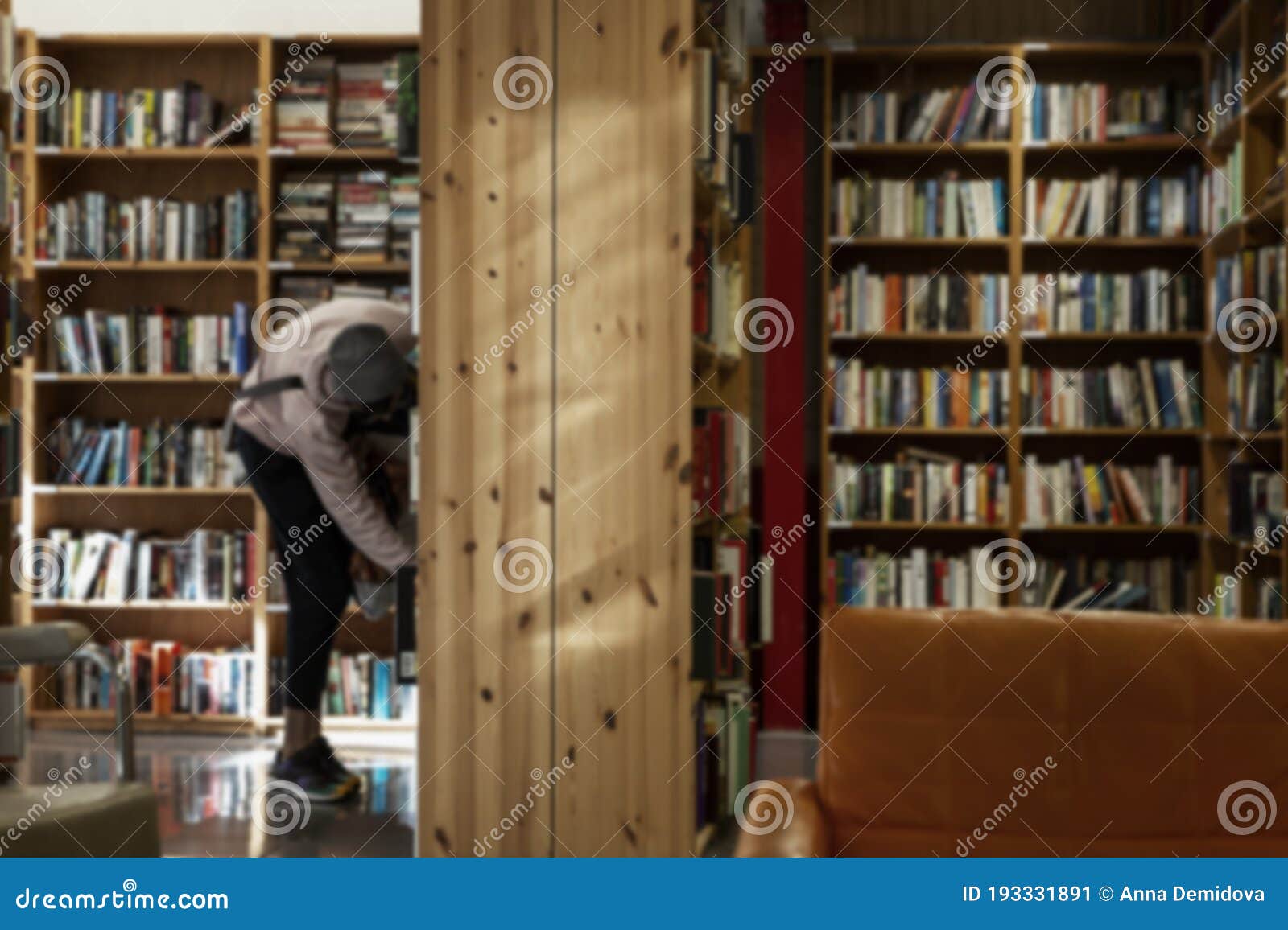 Young Guy Looking for Books in the Library with Wooden Bookcases ...