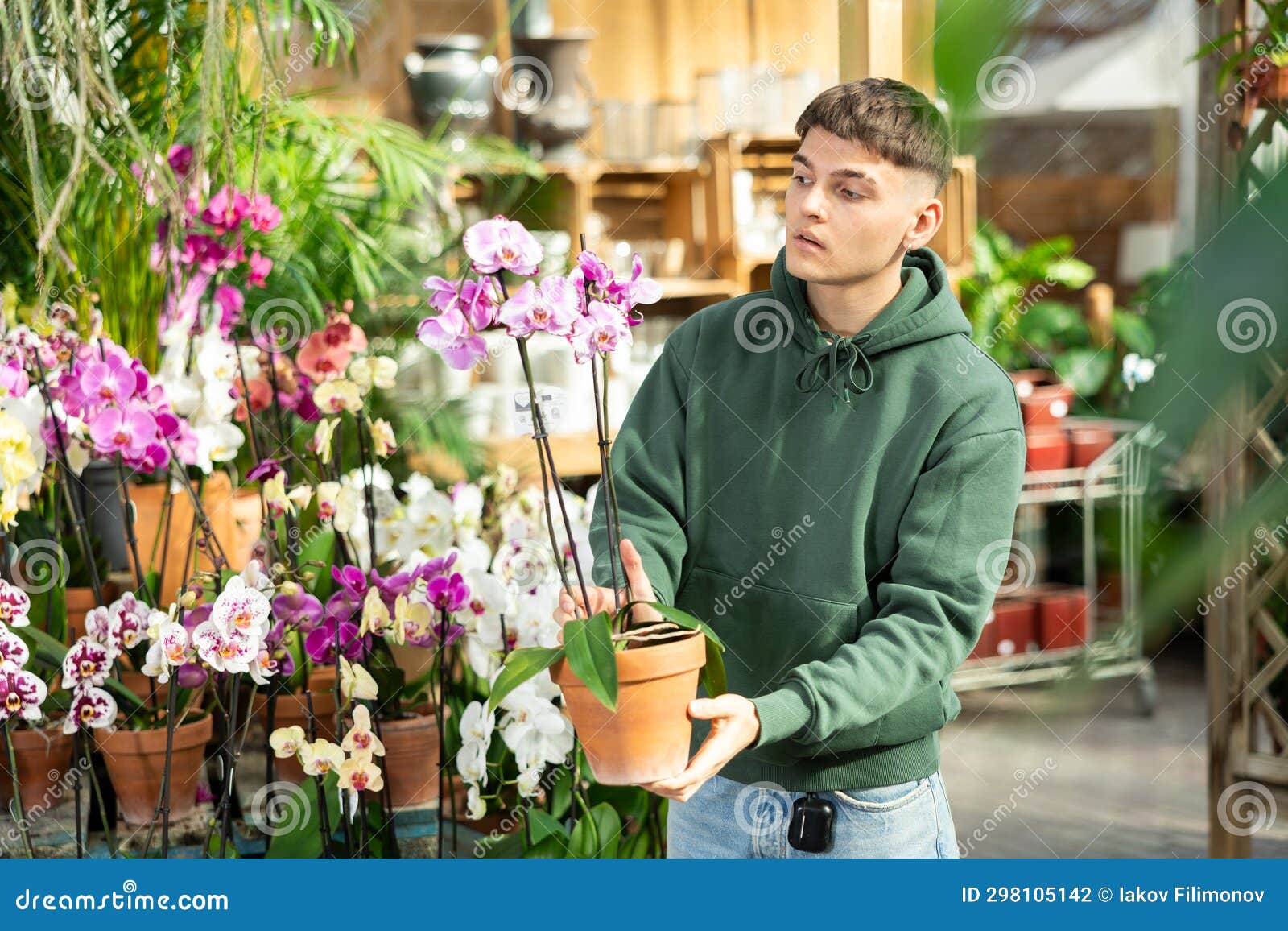 Young Guy Lovingly Selects a Flower Pot with Orchid Flowers in Flower ...