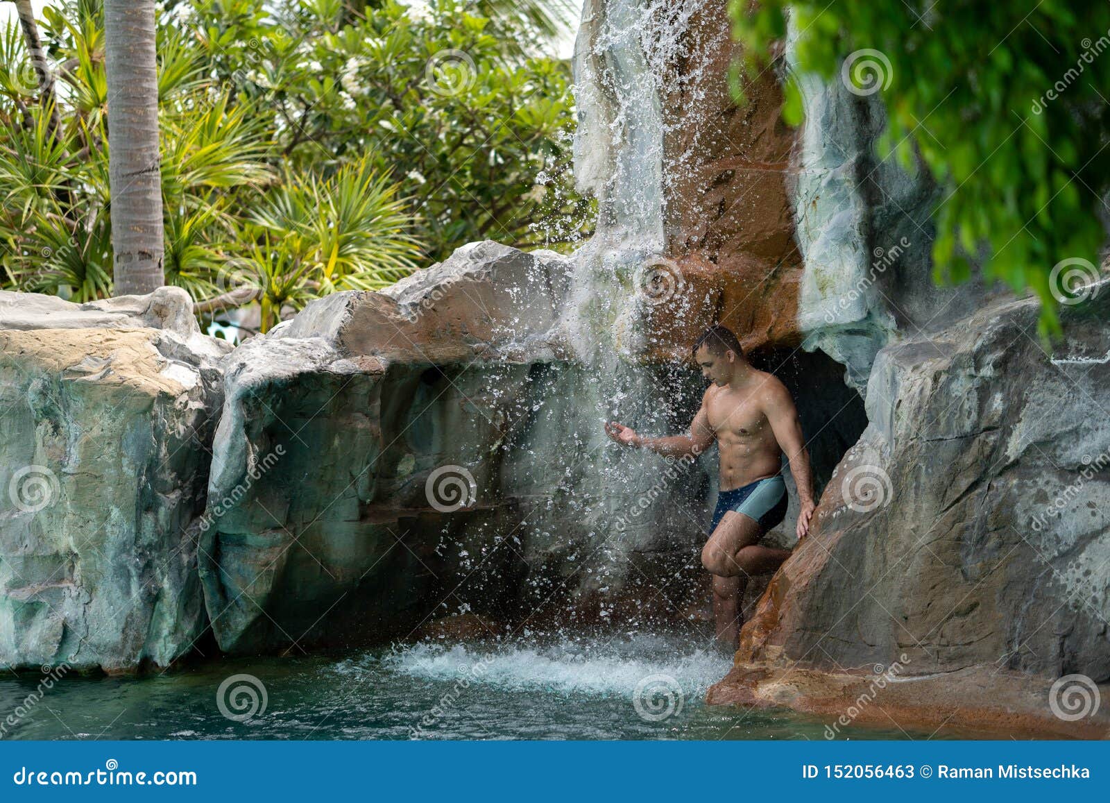 A Young Guy Stands Under Artificial Waterfalls in the Pool on Site ...