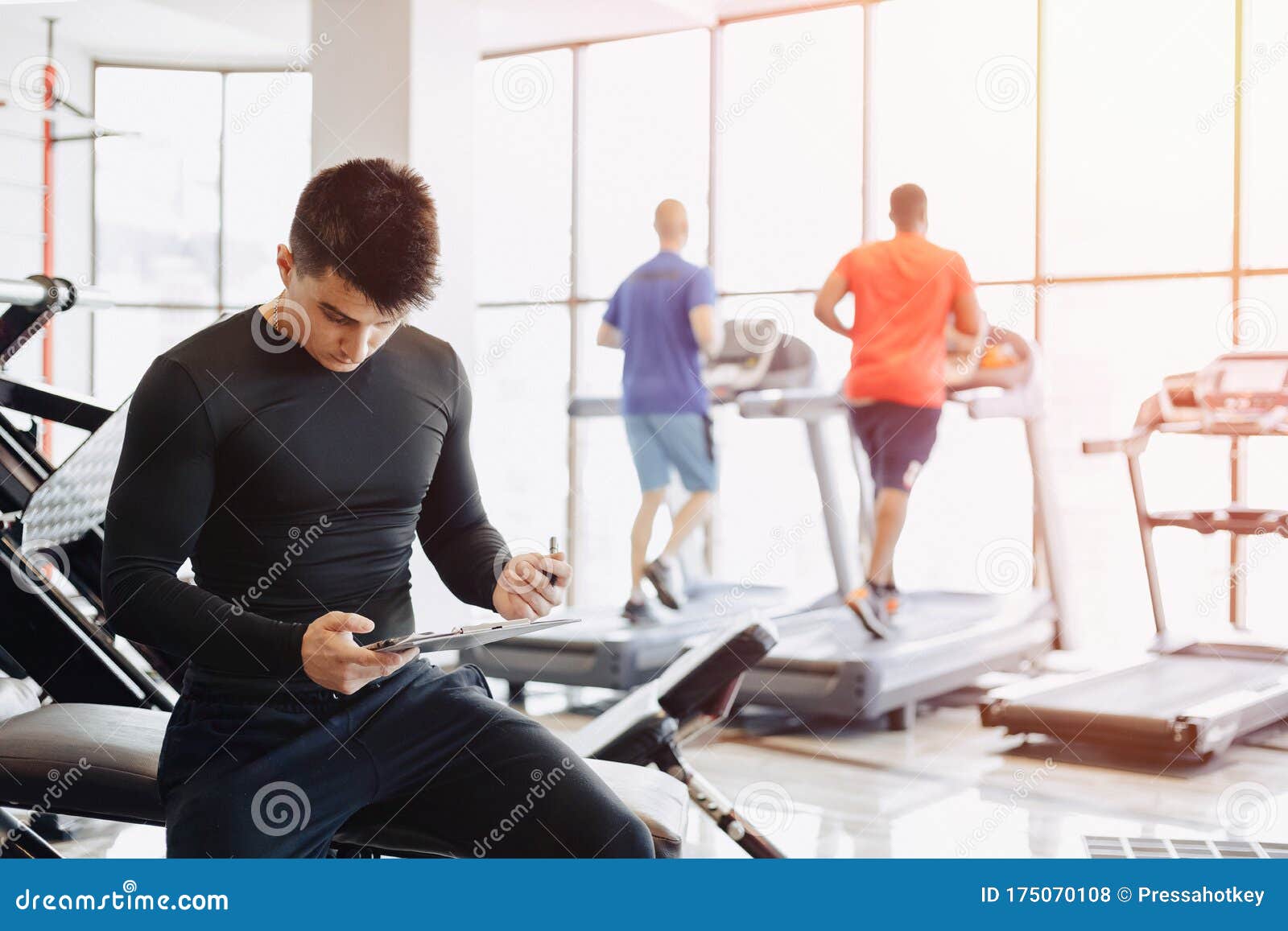 Young Guy Trainer Takes Notes in the Gym. Personal Trainer for Sports ...