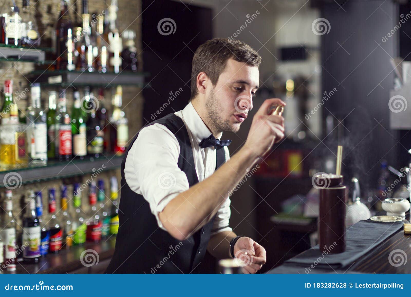 A Young Guy Working As a Bartender Behind a Bar is Preparing Drinks ...