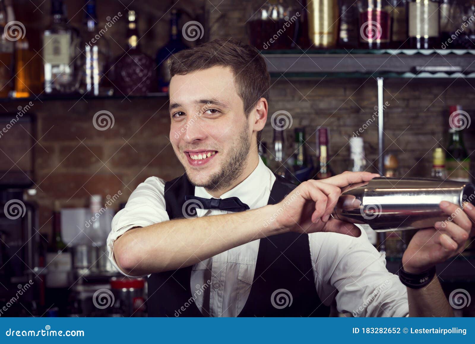 A Young Guy Working As a Bartender Behind a Bar is Preparing Drinks ...