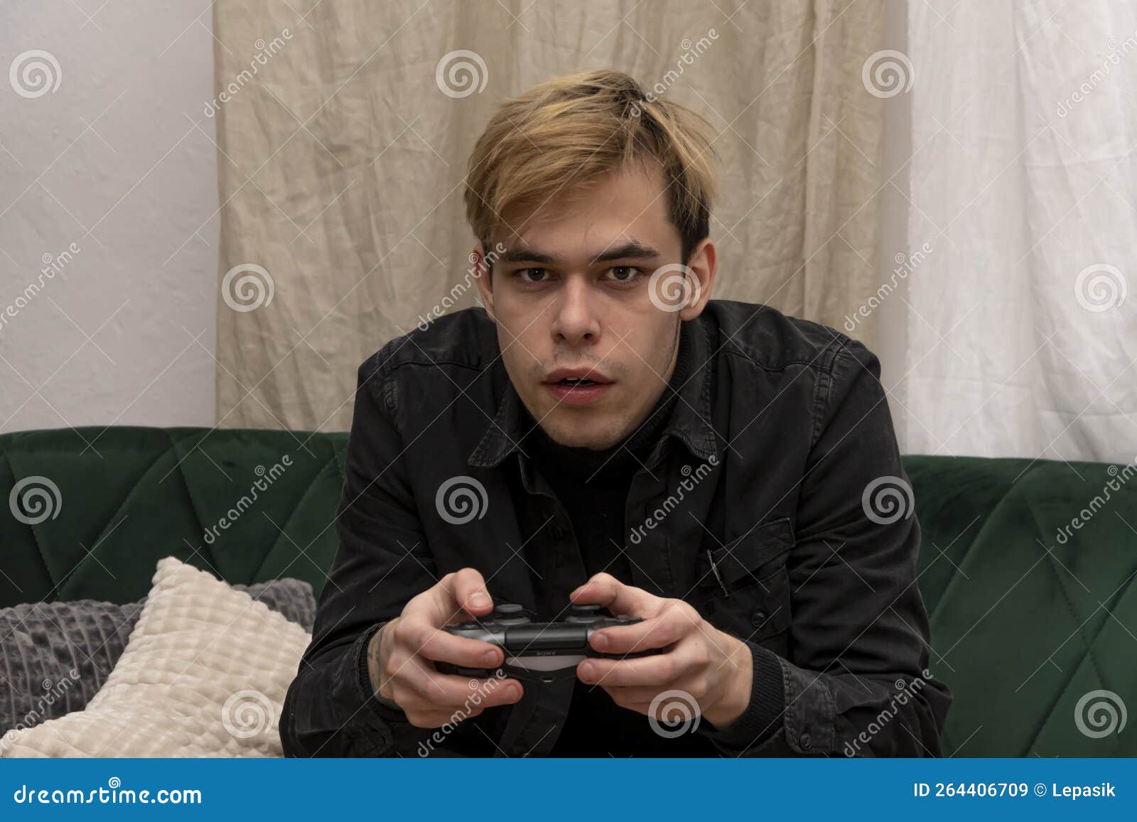 A Young Guy 20-25 Years Old is Playing a Game Console on a Light ...