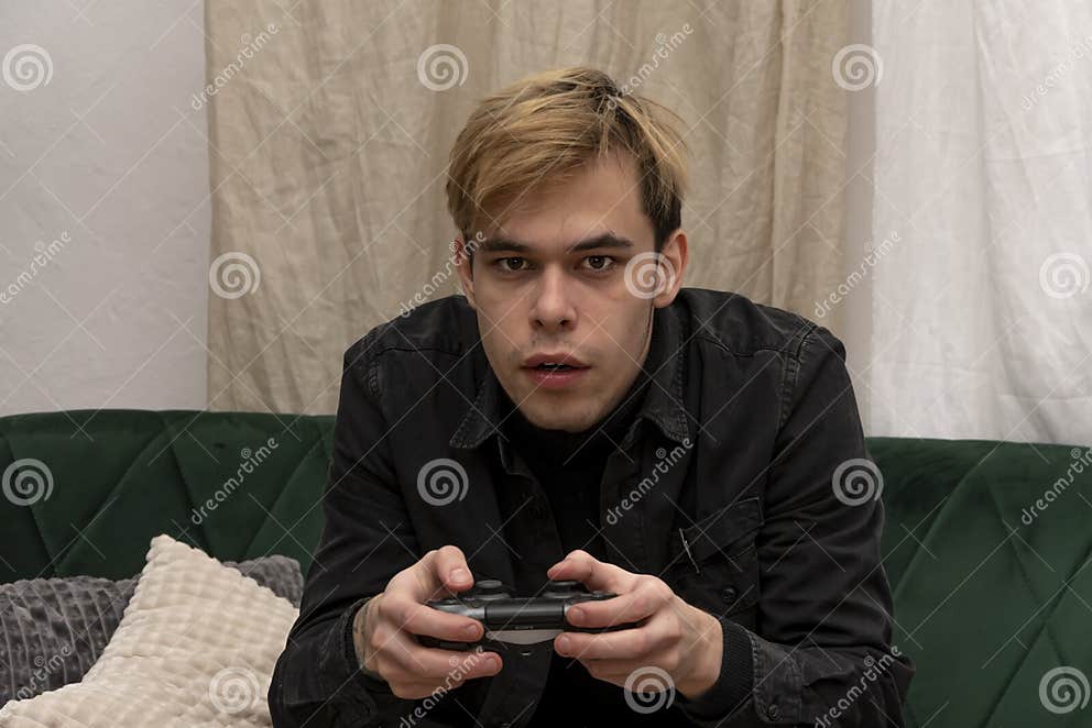 A Young Guy 20-25 Years Old is Playing a Game Console on a Light ...