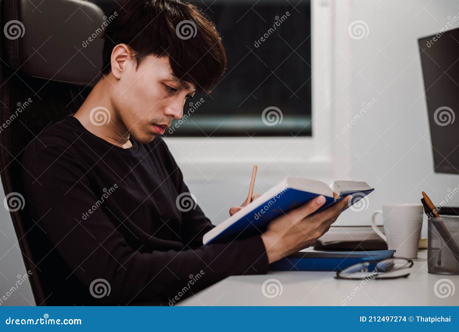 Young Handsome Asian Man Reading Book and Writing Note at Work Desk ...