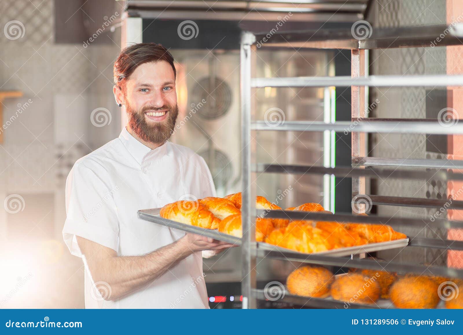 A Young Handsome Baker Takes Out Hot Fresh Baking from the Oven in the ...