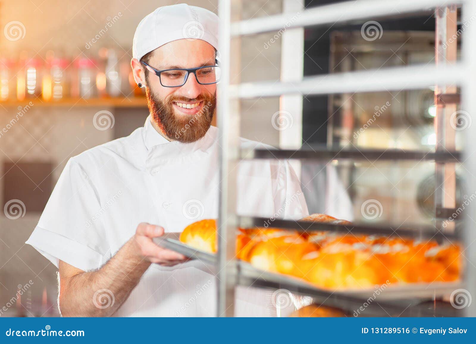 A Young Handsome Baker Takes Out Hot Fresh Baking from the Oven in the ...