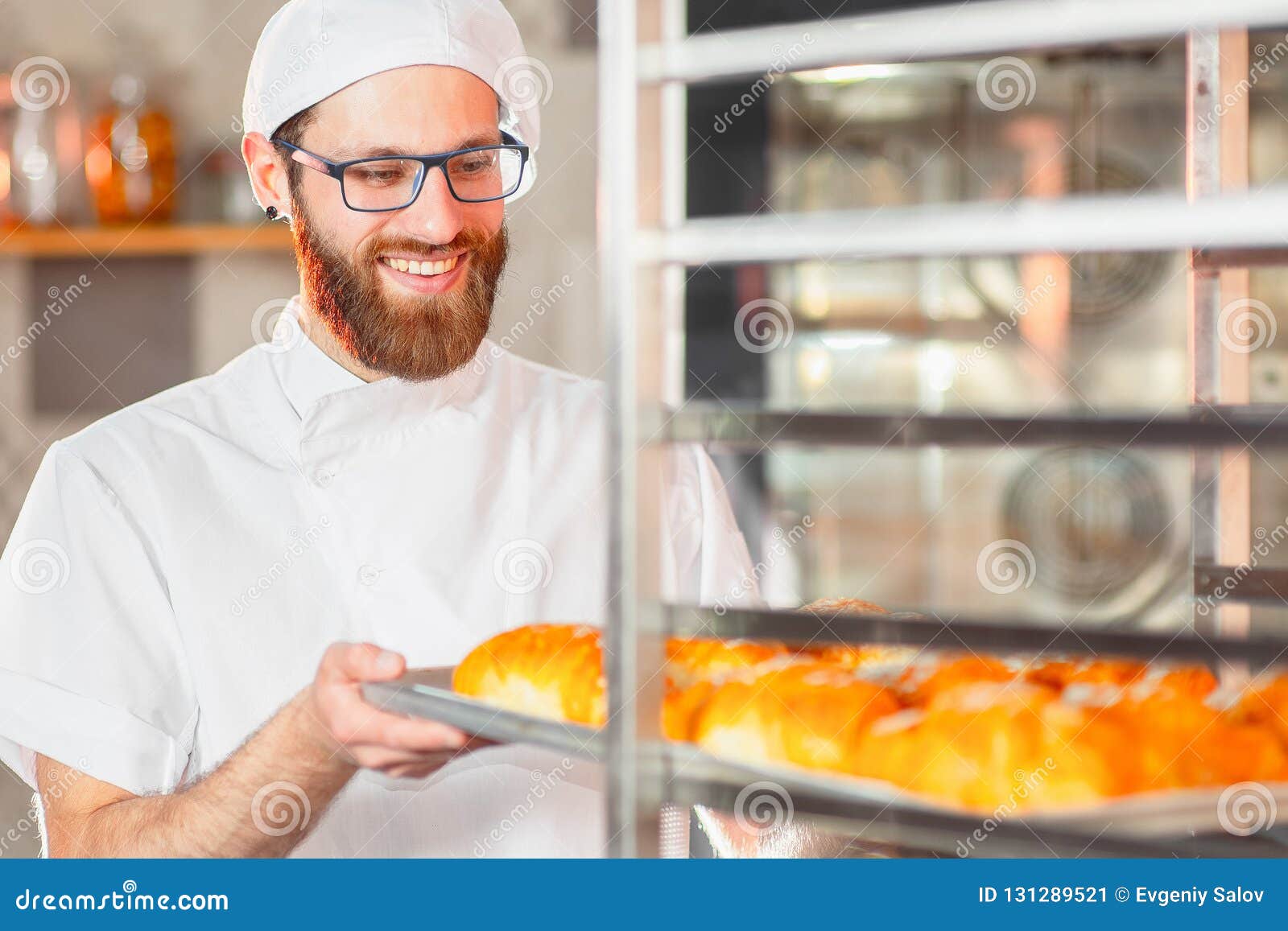 A Young Handsome Baker Takes Out Hot Fresh Baking from the Oven in the ...