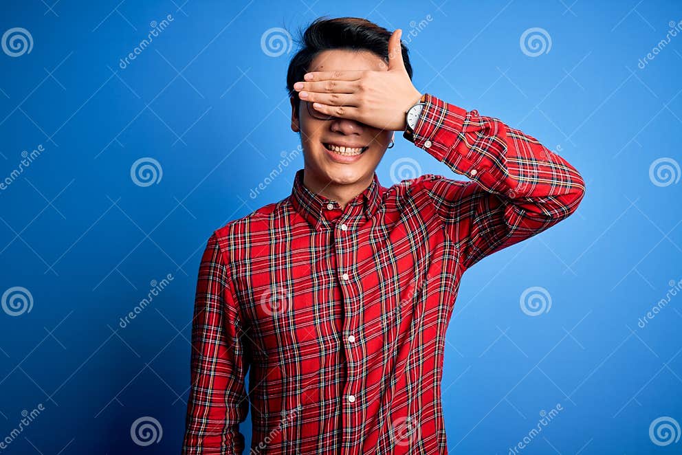 Young Handsome Chinese Man Wearing Casual Shirt And Glasses Over Blue