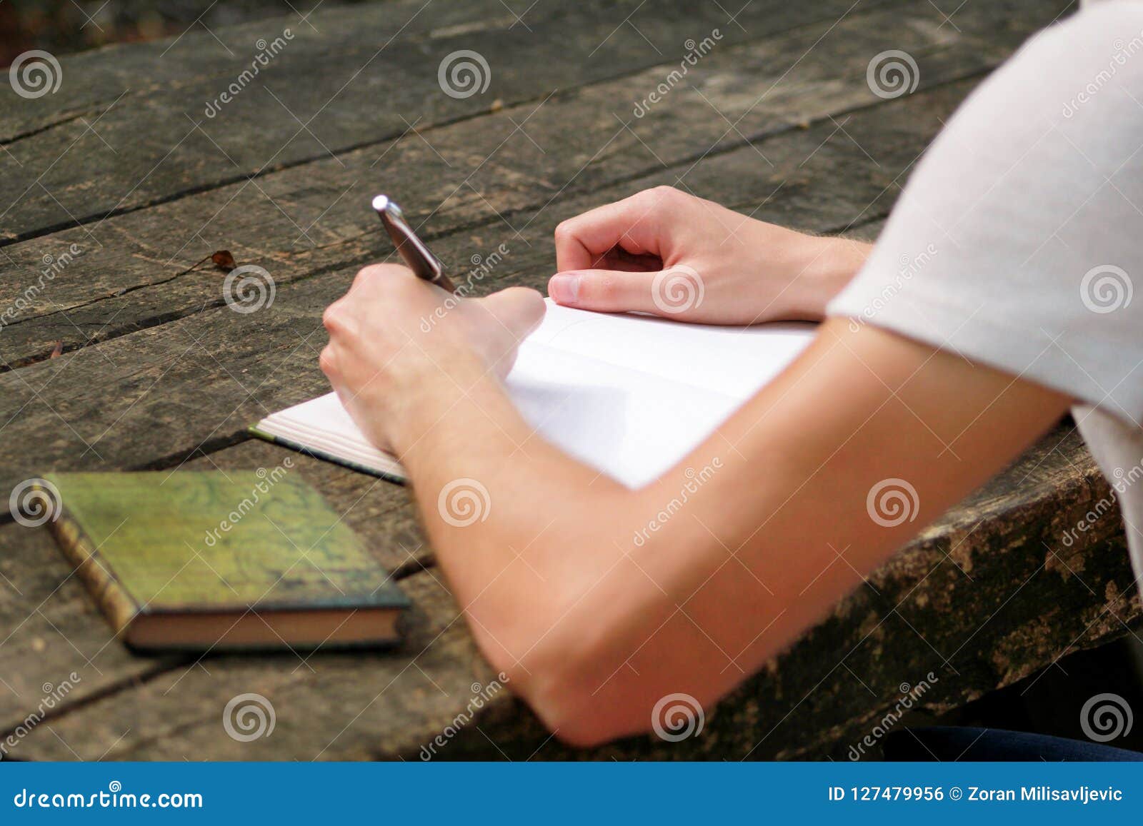 Young Handsome Guy Sitting at Wooden Table, Writing a Book, Doing ...
