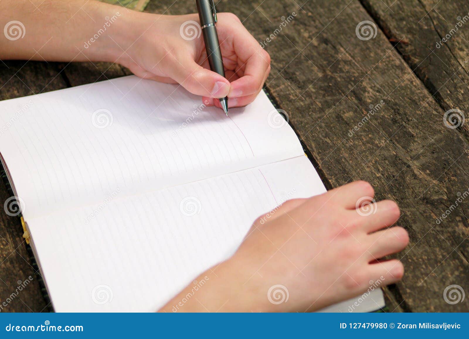 Young Handsome Guy Sitting at Wooden Table, Writing a Book, Doing ...