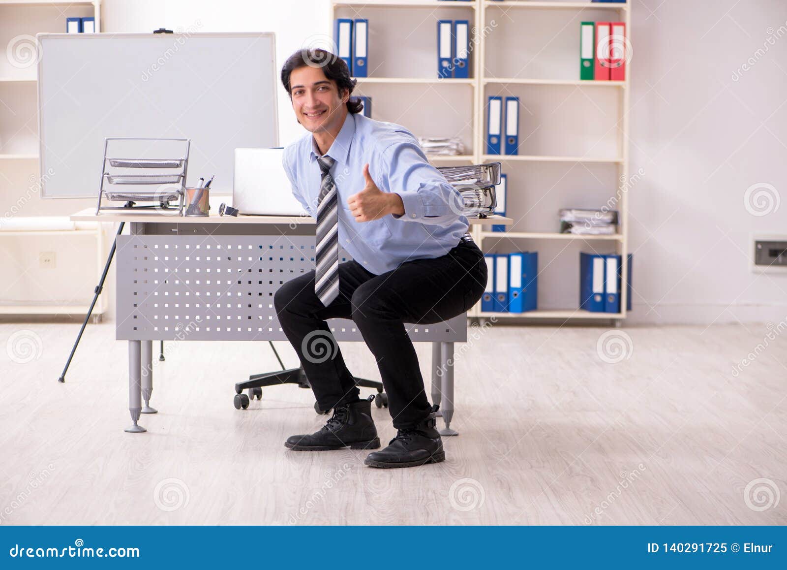 The Young Handsome Male Employee Doing Exercises in the Office Stock ...