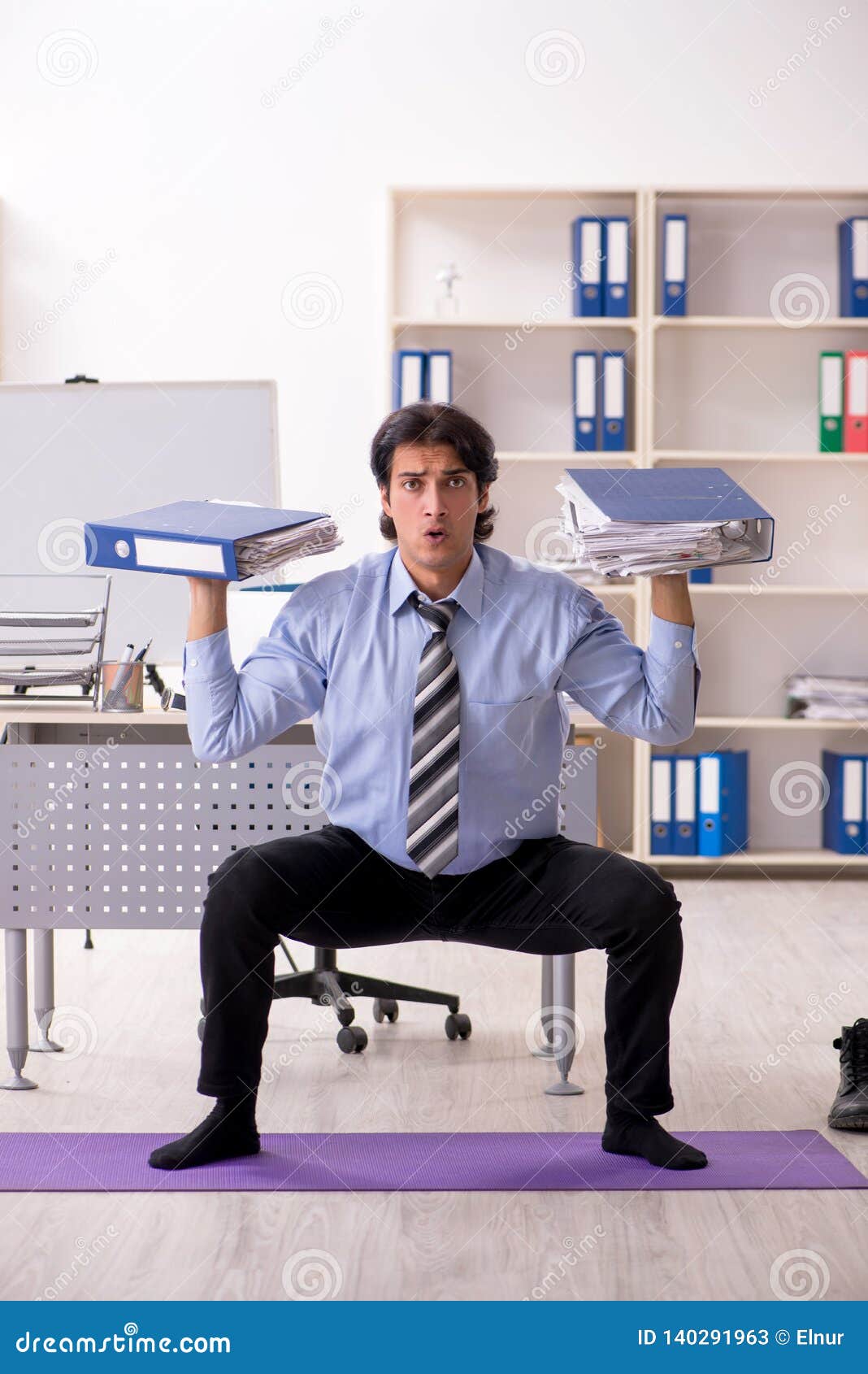 The Young Handsome Male Employee Doing Exercises in the Office Stock ...
