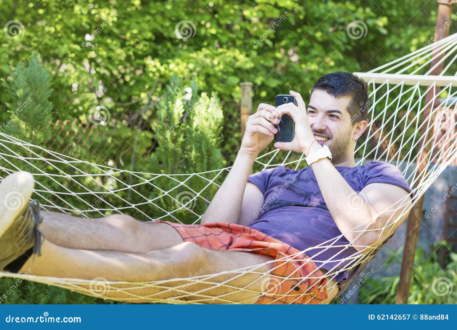 Young Handsome Man Relaxing in Hammock and Playing with His Phone Stock ...