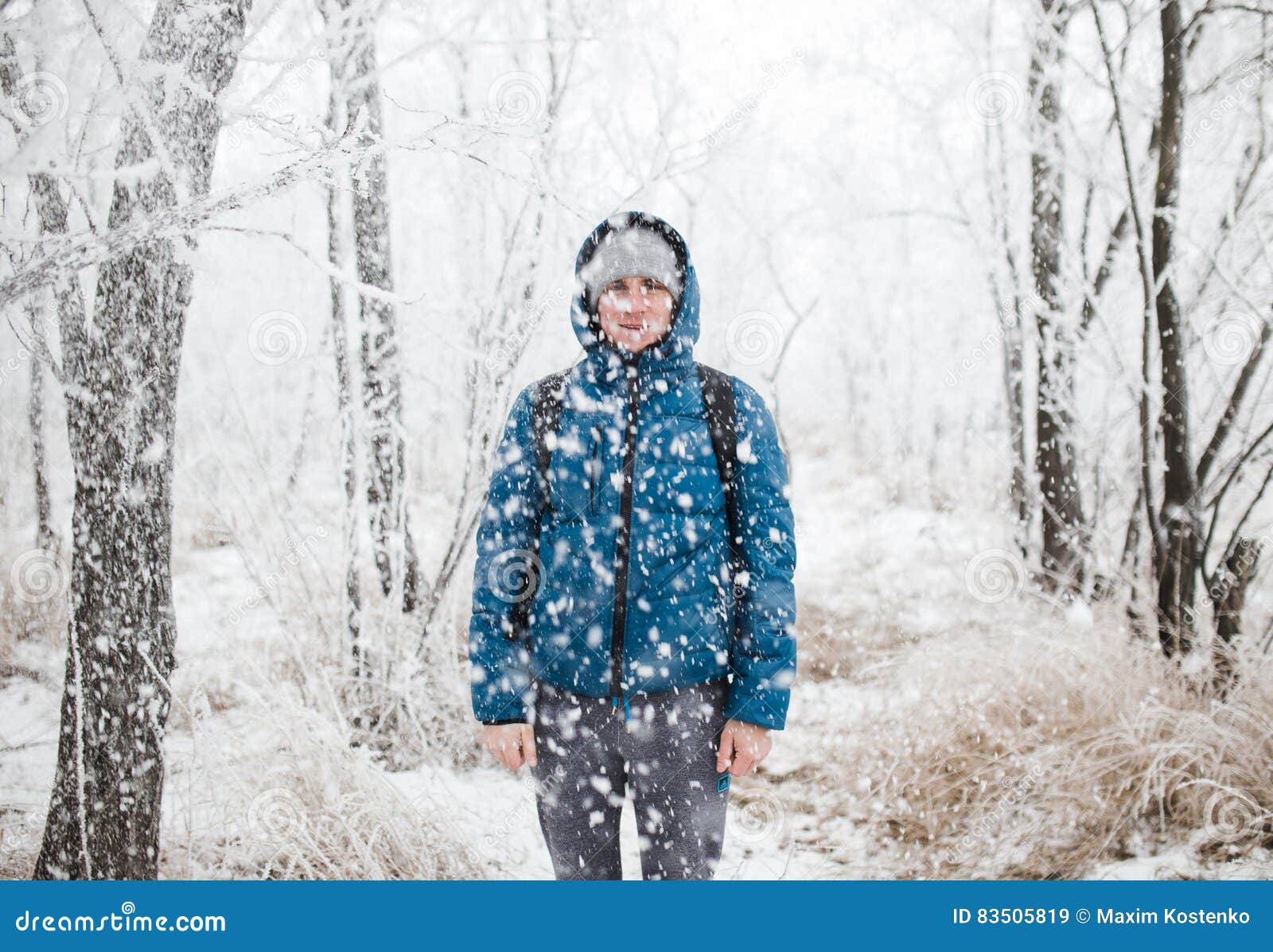 Young Handsome Man Standing In Snowfall On Background Of Snowy Forest ... Young Handsome Man Standing In Snowfall On Background Of Snowy Forest ...