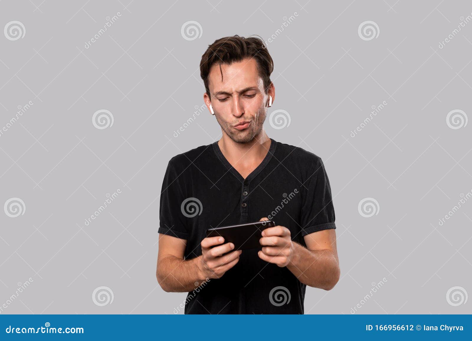 Young Handsome Man with Wireless Earbuds Holding Smartphone. Stock ...