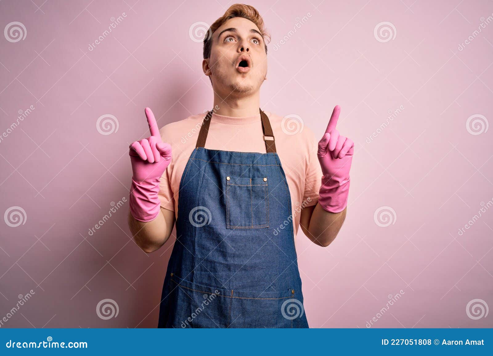Young Handsome Redhead Cleaner Man Doing Housework Wearing Apron And Gloves Amazed And Surprised