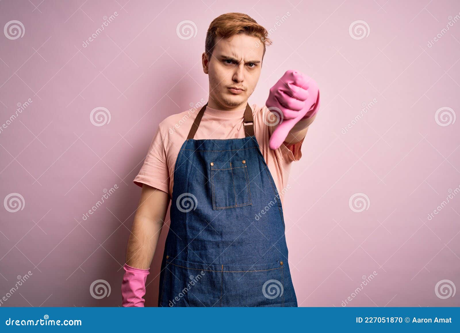 Young Handsome Redhead Cleaner Man Doing Housework Wearing Apron And Gloves Looking Unhappy And