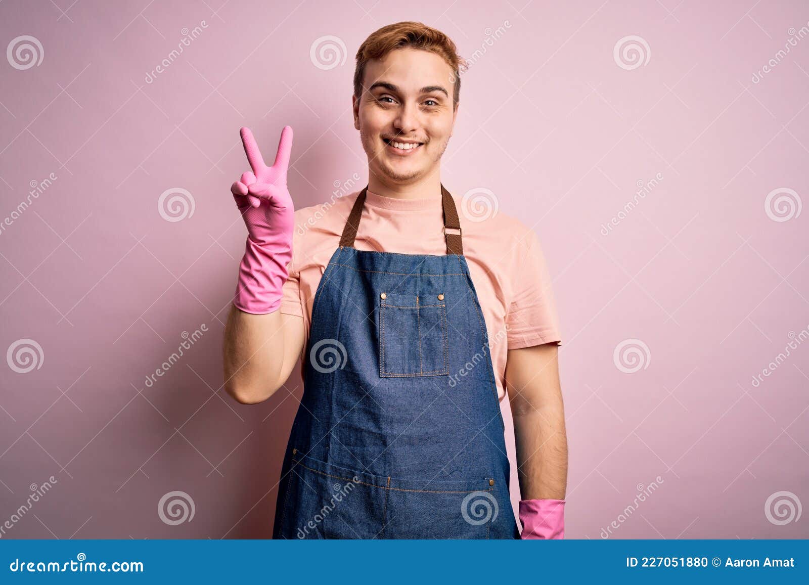 Young Handsome Redhead Cleaner Man Doing Housework Wearing Apron And Gloves Showing And Pointing