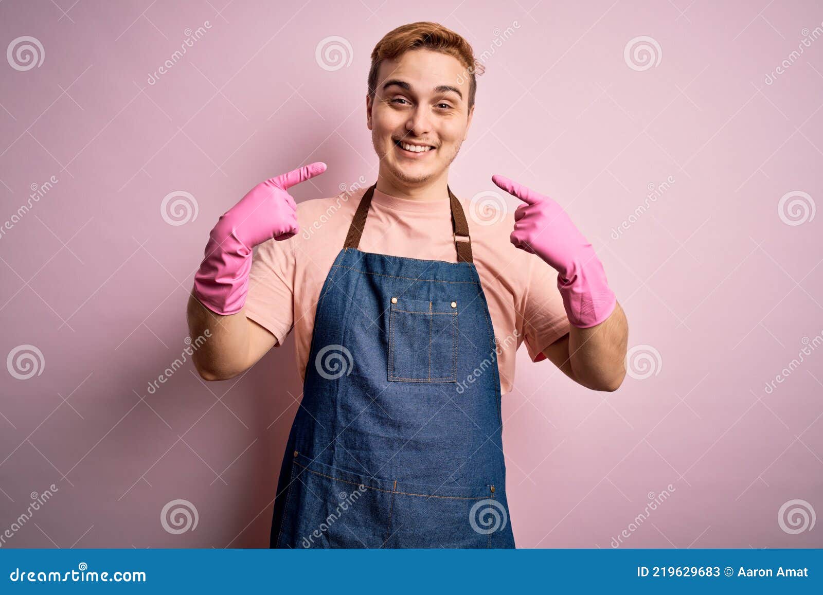 Young Handsome Redhead Cleaner Man Doing Housework Wearing Apron And Gloves Smiling Cheerful