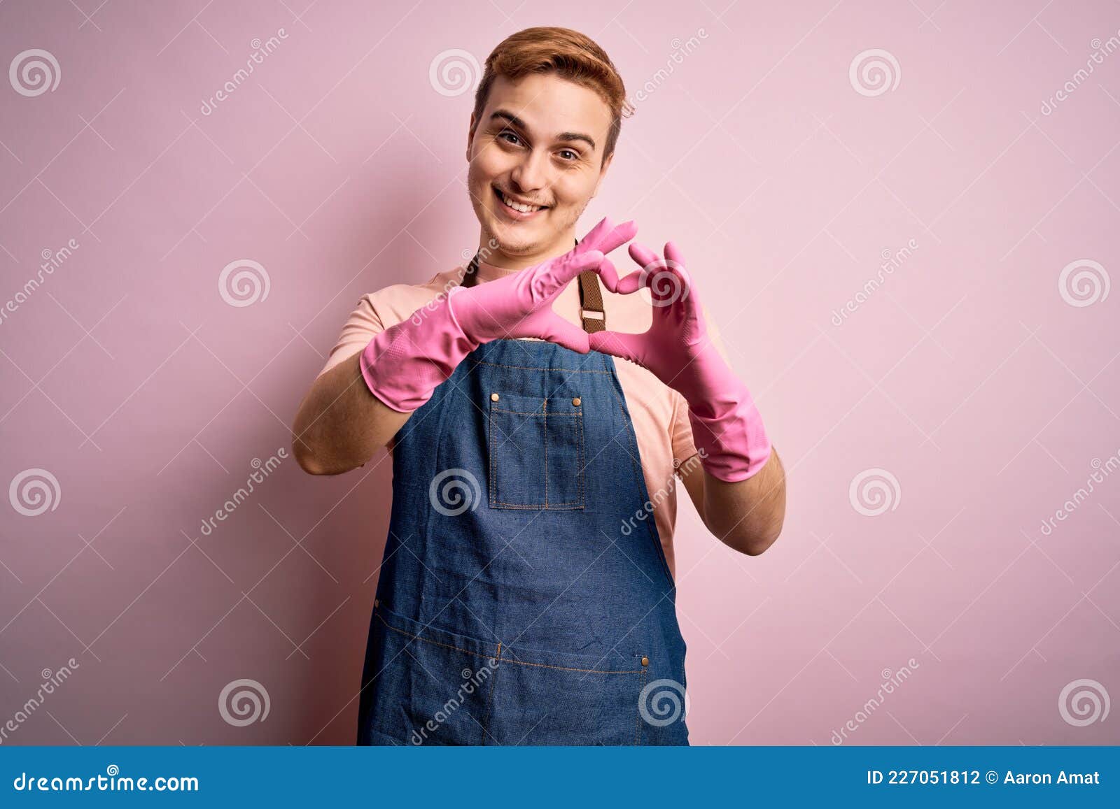 Young Handsome Redhead Cleaner Man Doing Housework Wearing Apron And Gloves Smiling In Love