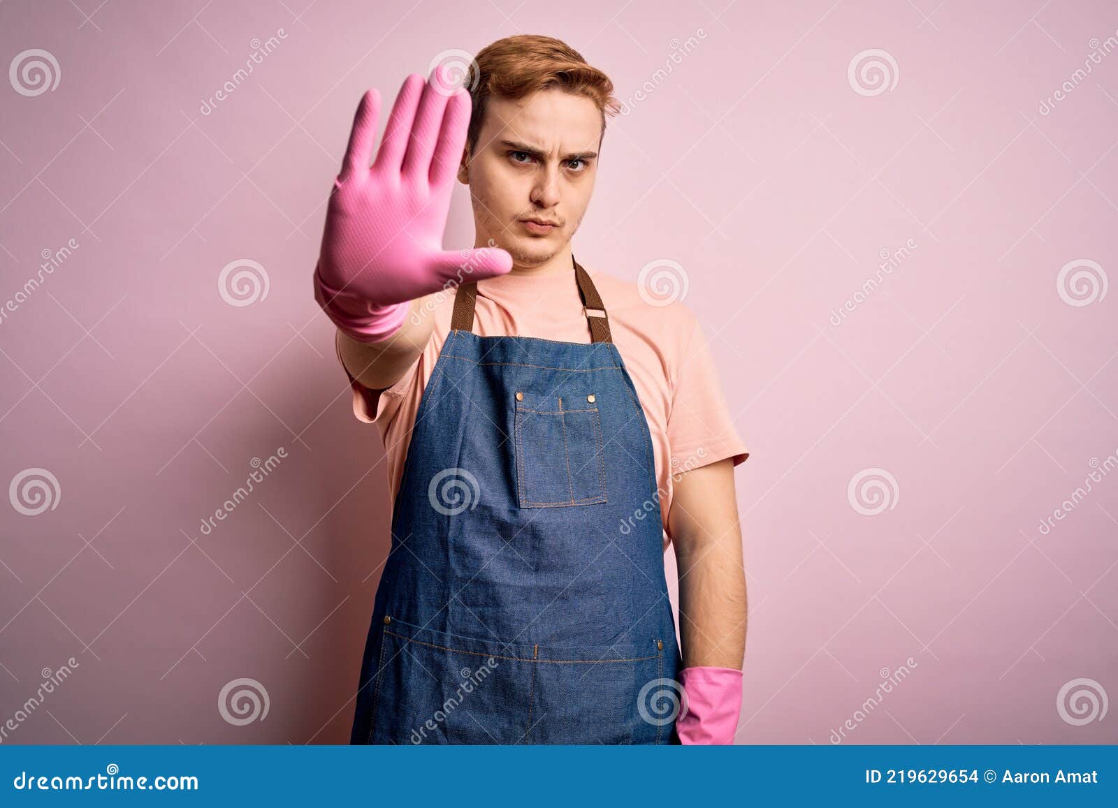 Young Handsome Redhead Cleaner Man Doing Housework Wearing Apron And Gloves Doing Stop Sing With
