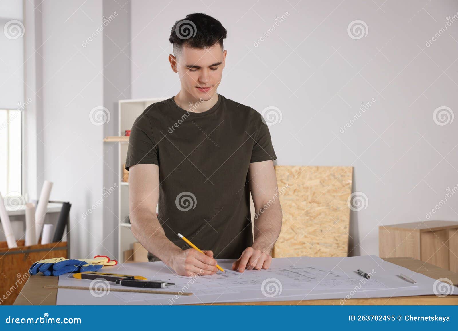 Young Handyman Working with Blueprints at Table in Room Stock Image ...