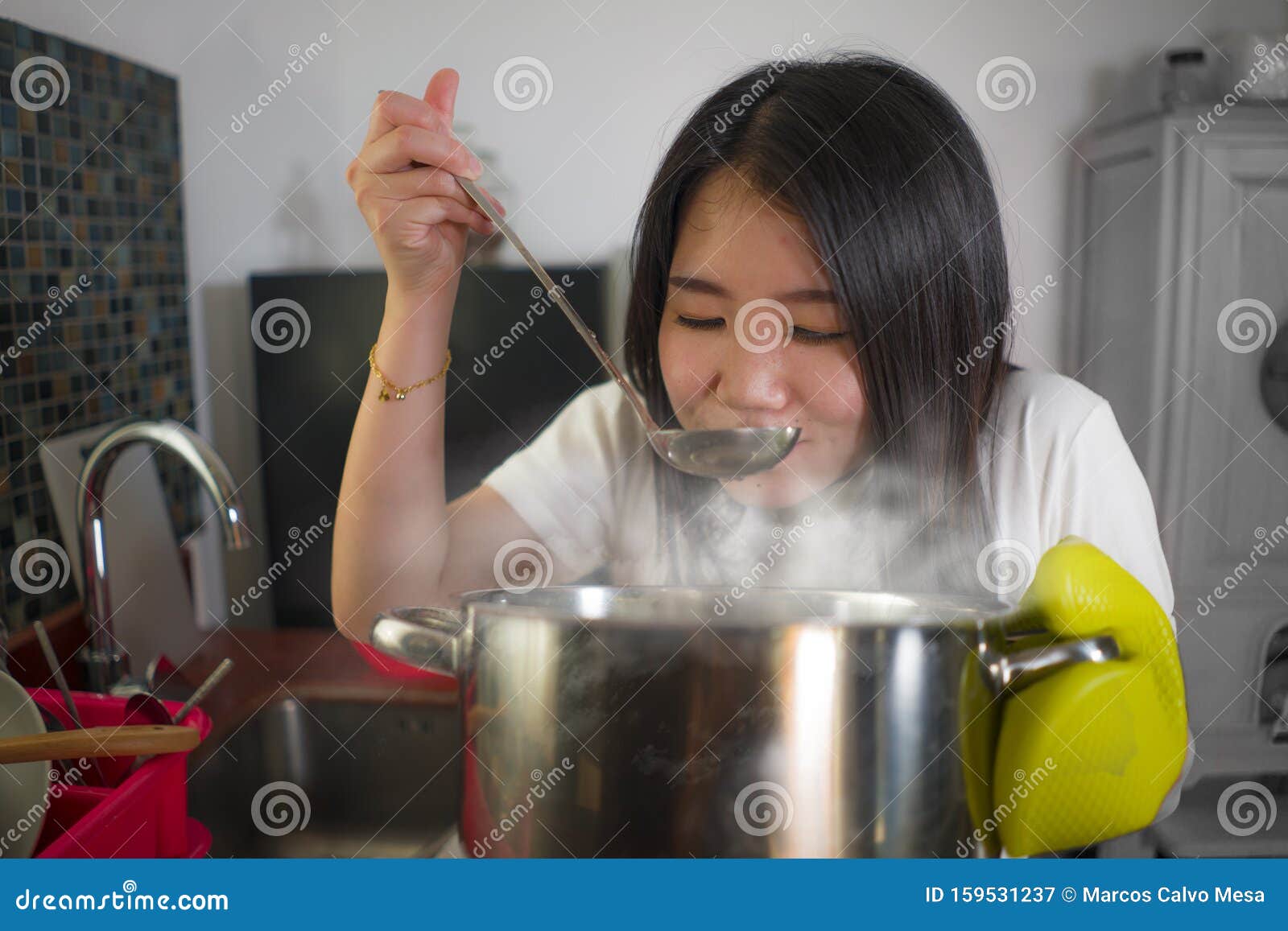Young Happy And Beautiful Korean Woman In Kitchen Apron And Glove