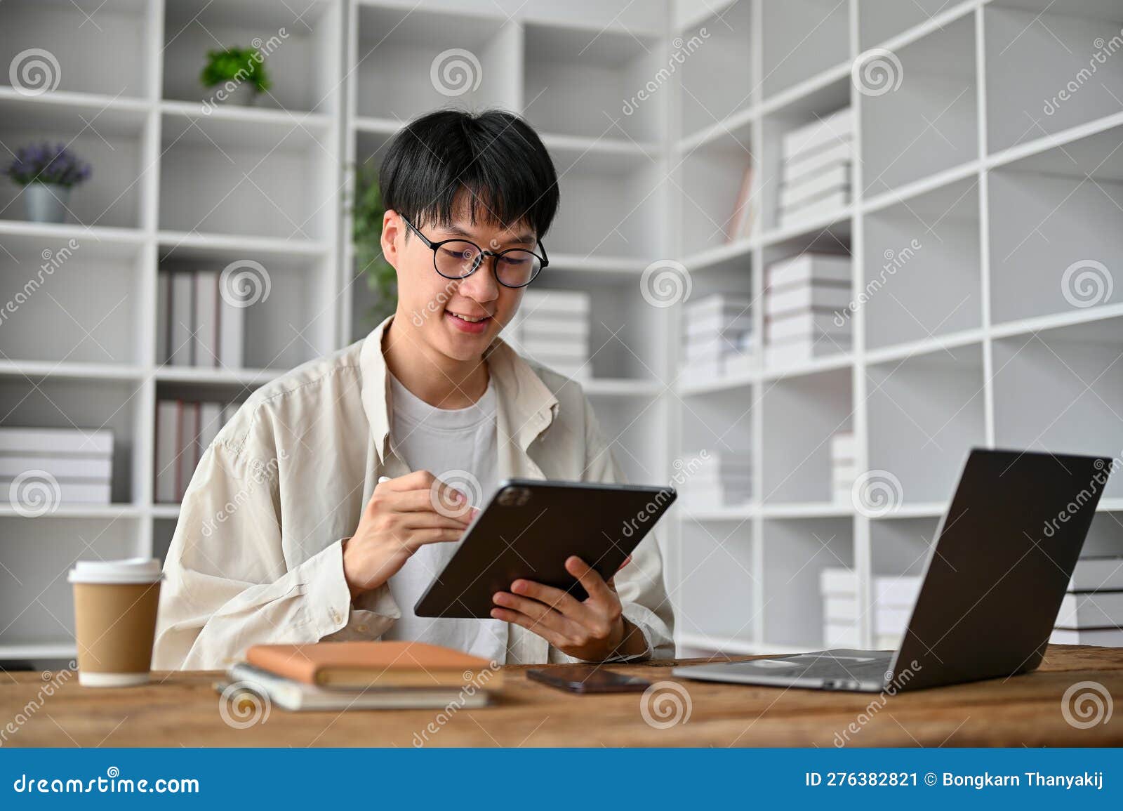 Young Happy College Student with Glasses Using Tablet in the Study ...