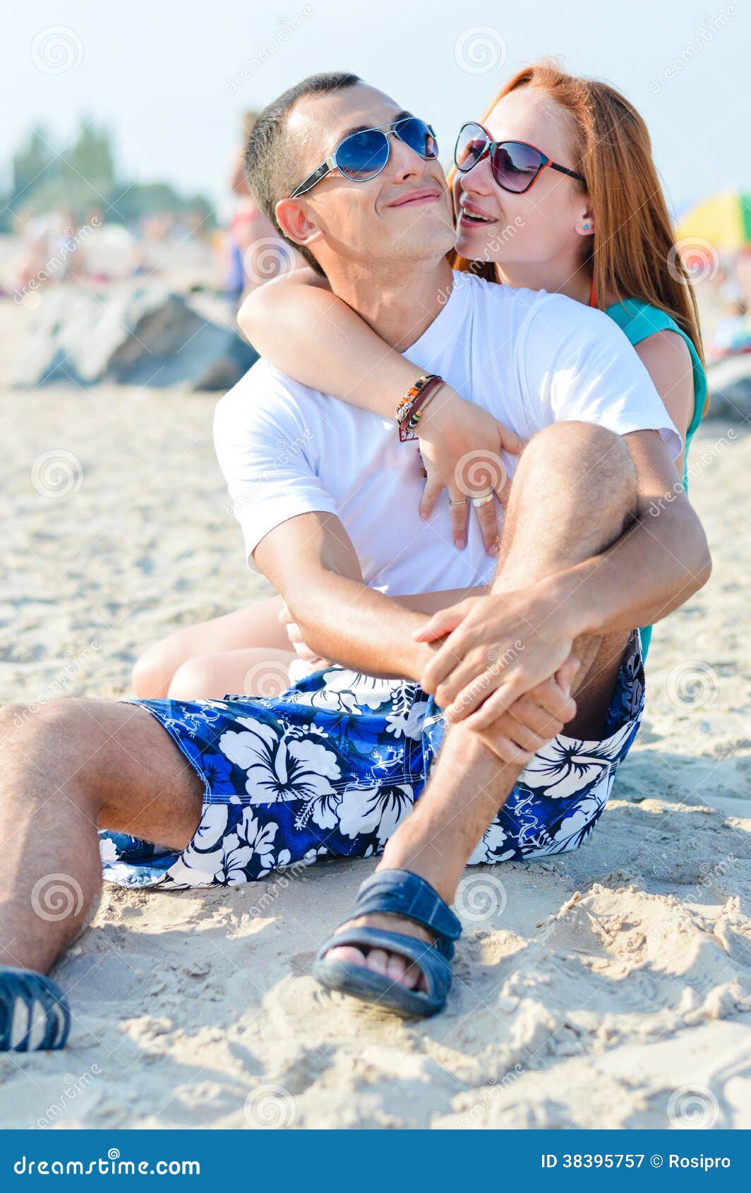 Young Happy Couple Sitting On Sea Beach And Embracing Stock Image