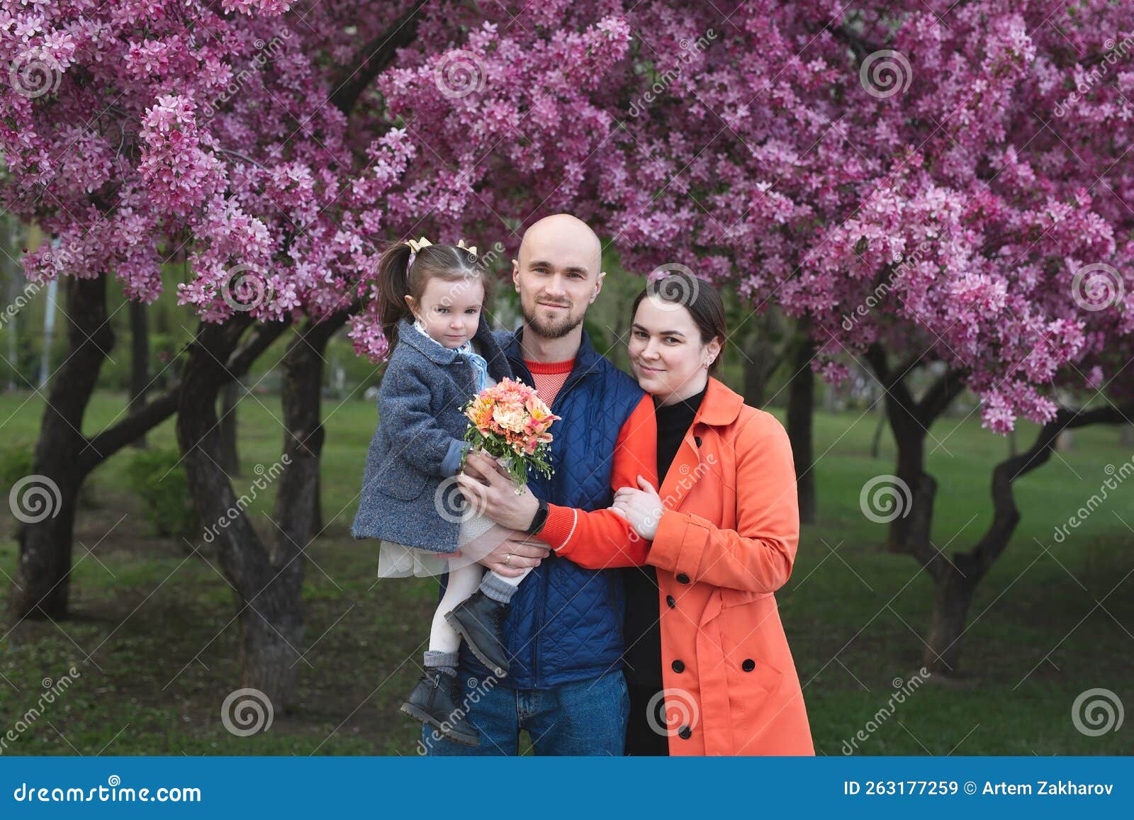 Young Happy Family in the Park in Spring on the Background of a ...