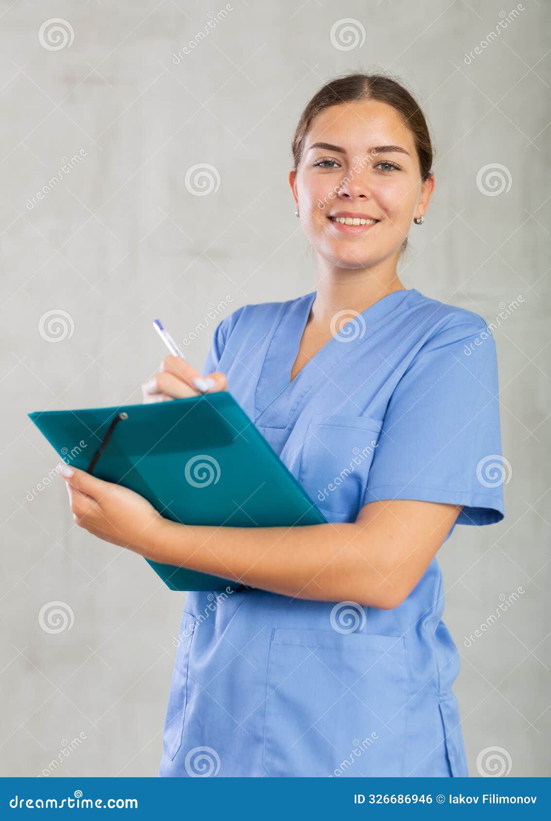 Young Happy Female Nurse Writing in File with Papers Stock Photo ...
