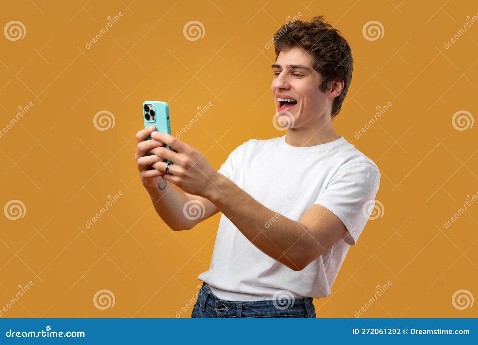 Young Happy Man Looking at His Phone Against Yellow Background Stock ...
