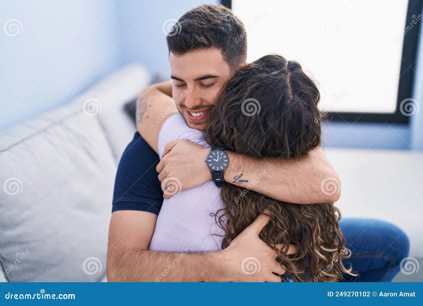 Young Hispanic Couple Hugging Each Other Sitting on Sofa at Home Stock ...