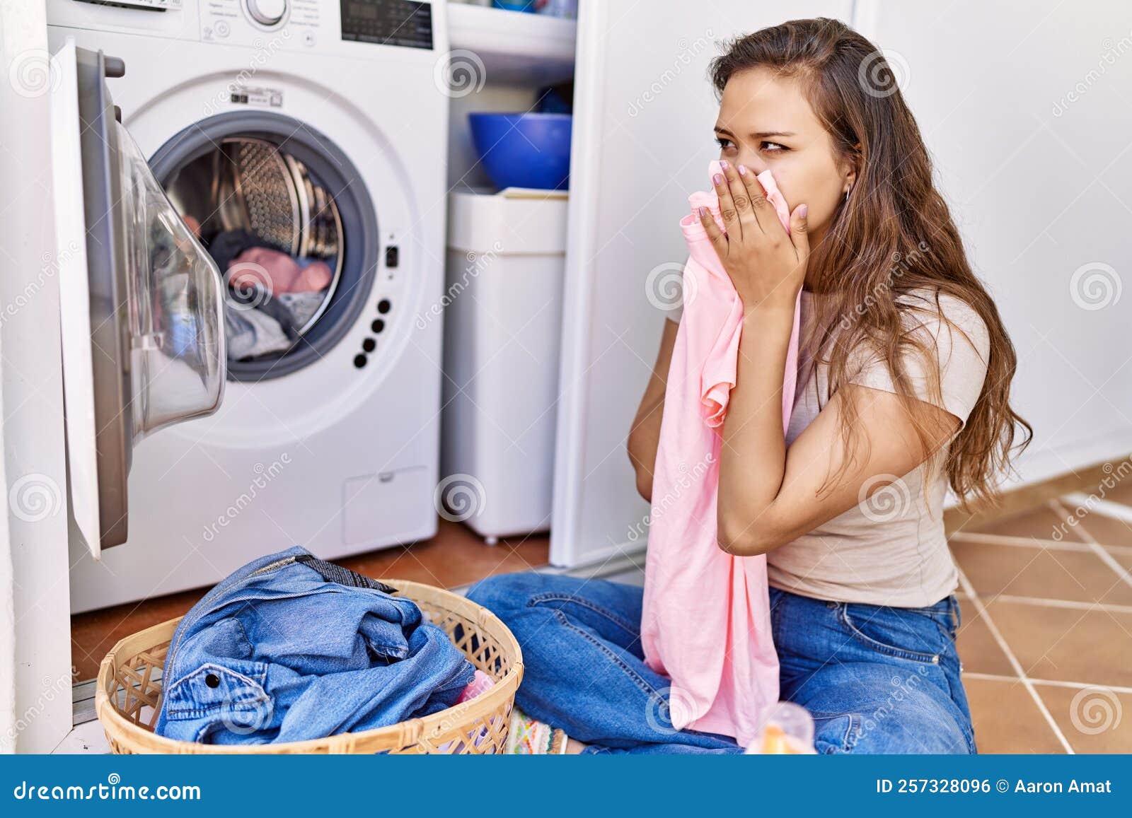Young Hispanic Girl Doing Laundry Smelling Clean Clothes at Home Stock ...