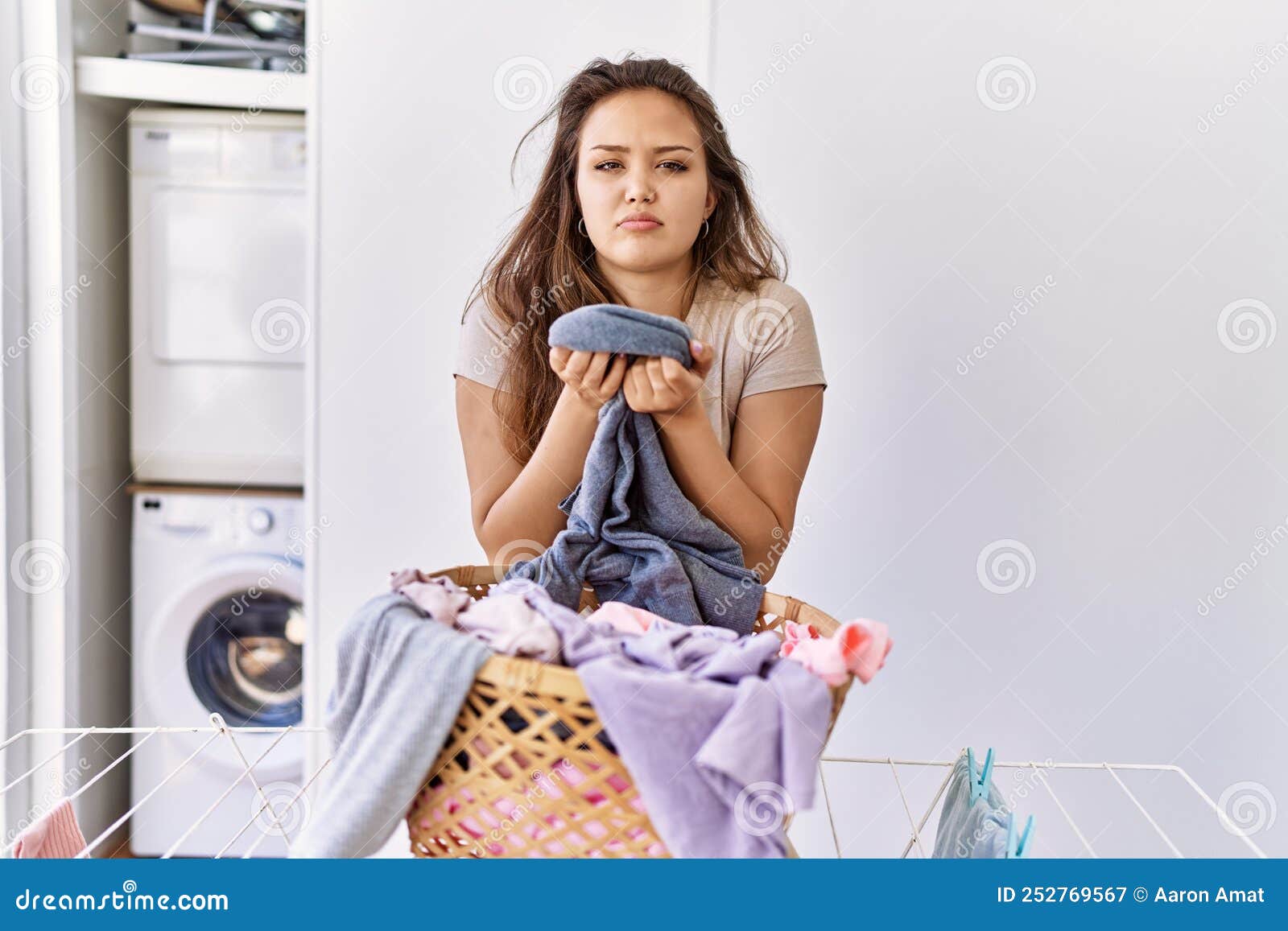 Young Hispanic Girl Doing Laundry Smelling Clothes at Home Stock Image ...