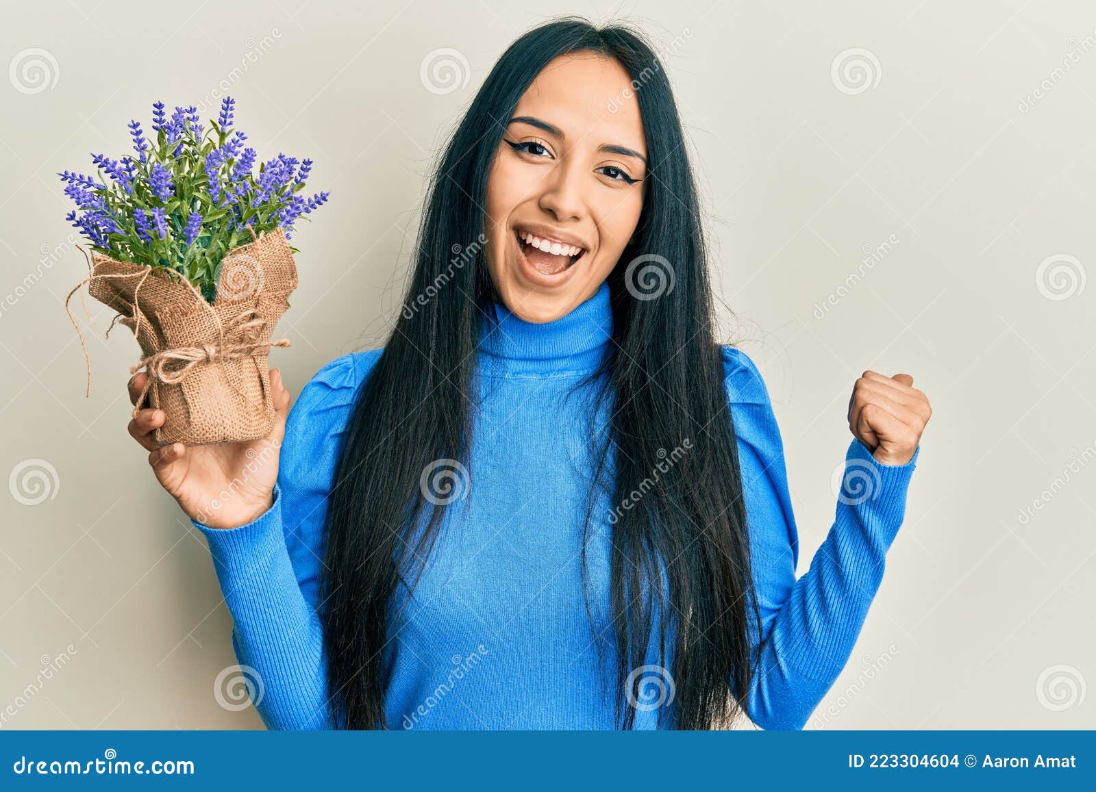 Young Hispanic Girl Holding Lavender Plant Pointing Thumb Up To The