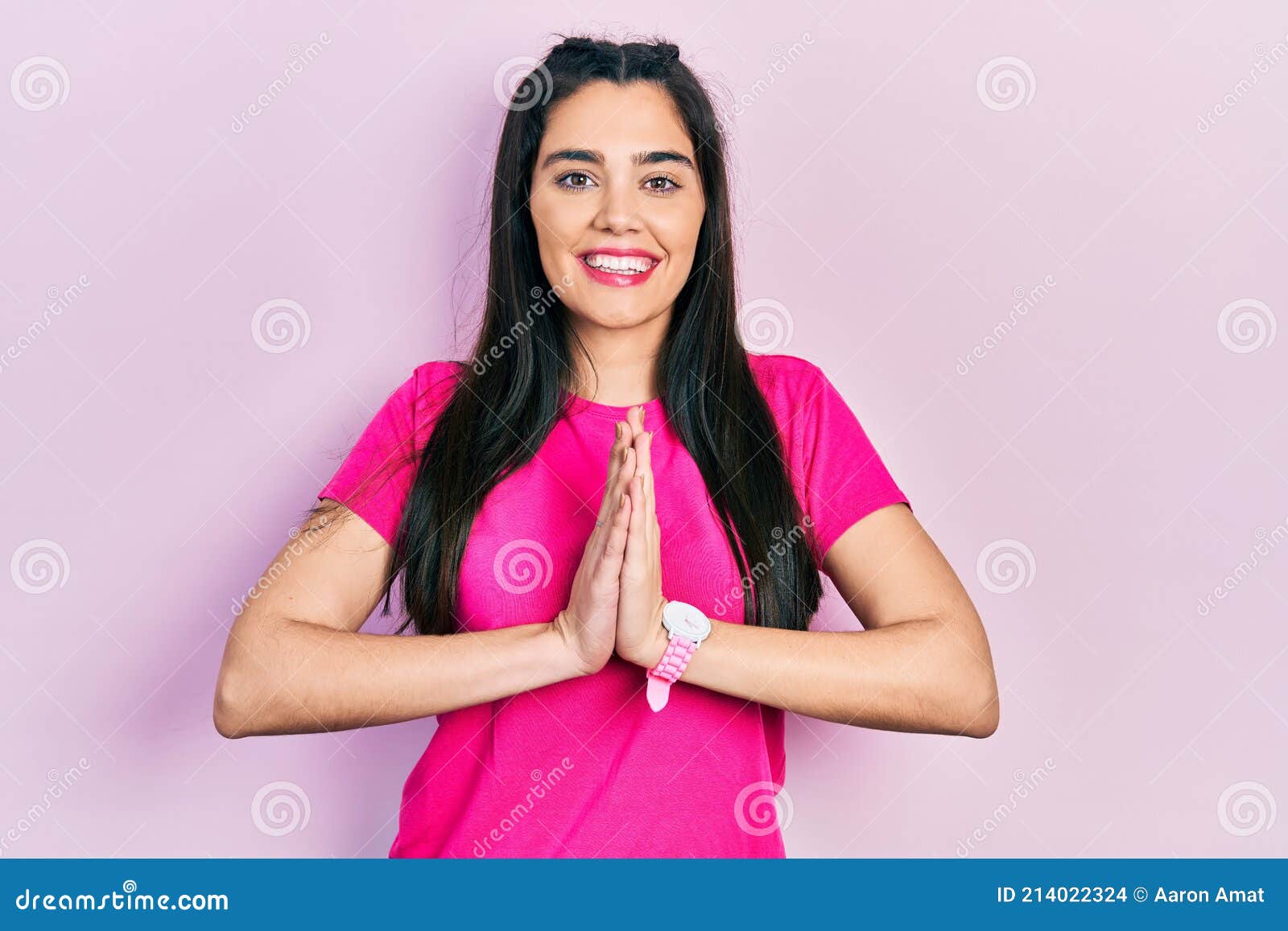 Young Hispanic Girl Wearing Casual Pink T Shirt Praying With Hands