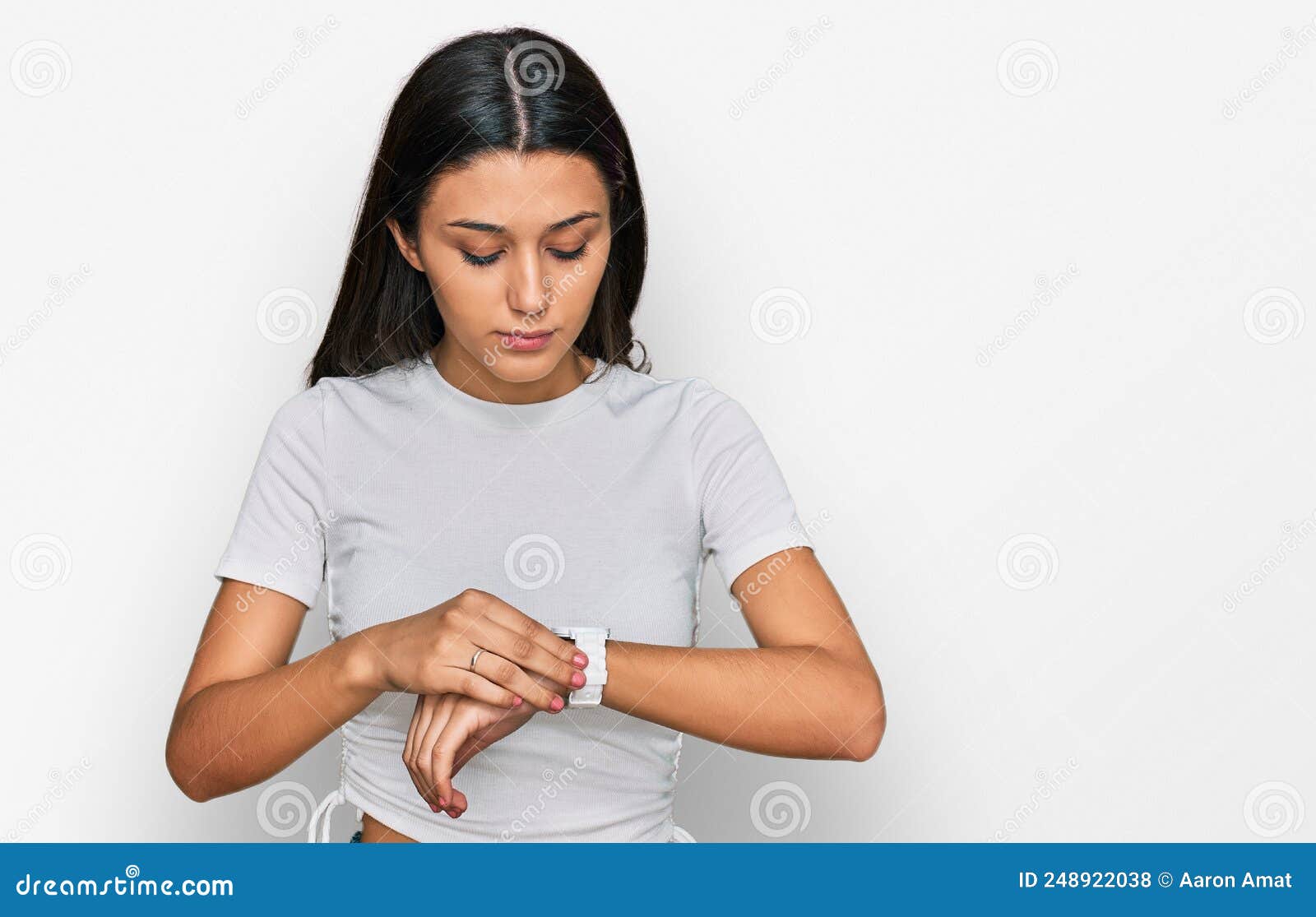 Young Hispanic Girl Wearing Casual White T Shirt Checking The Time On