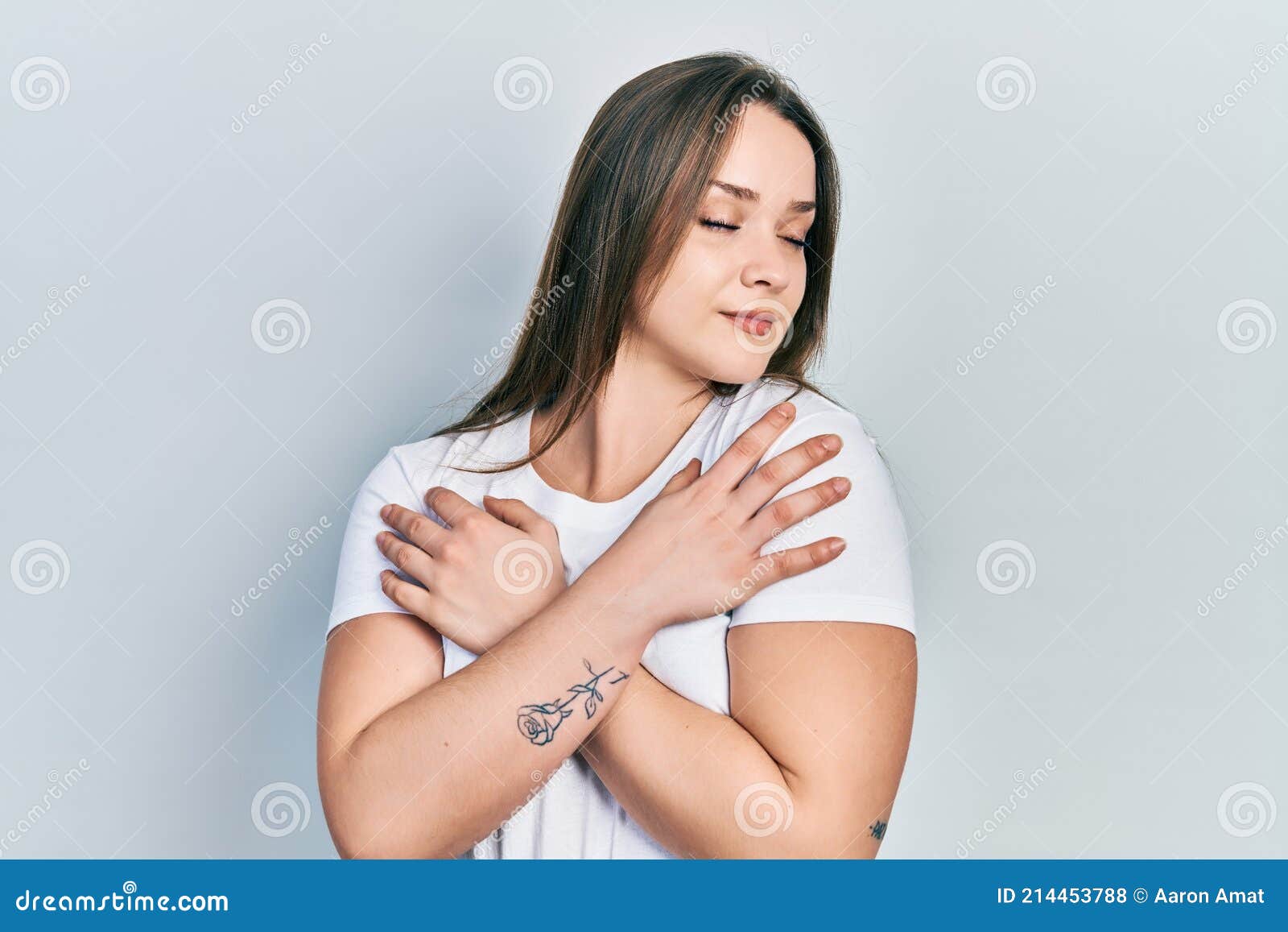 Young Hispanic Girl Wearing Casual White T Shirt Hugging Oneself Happy