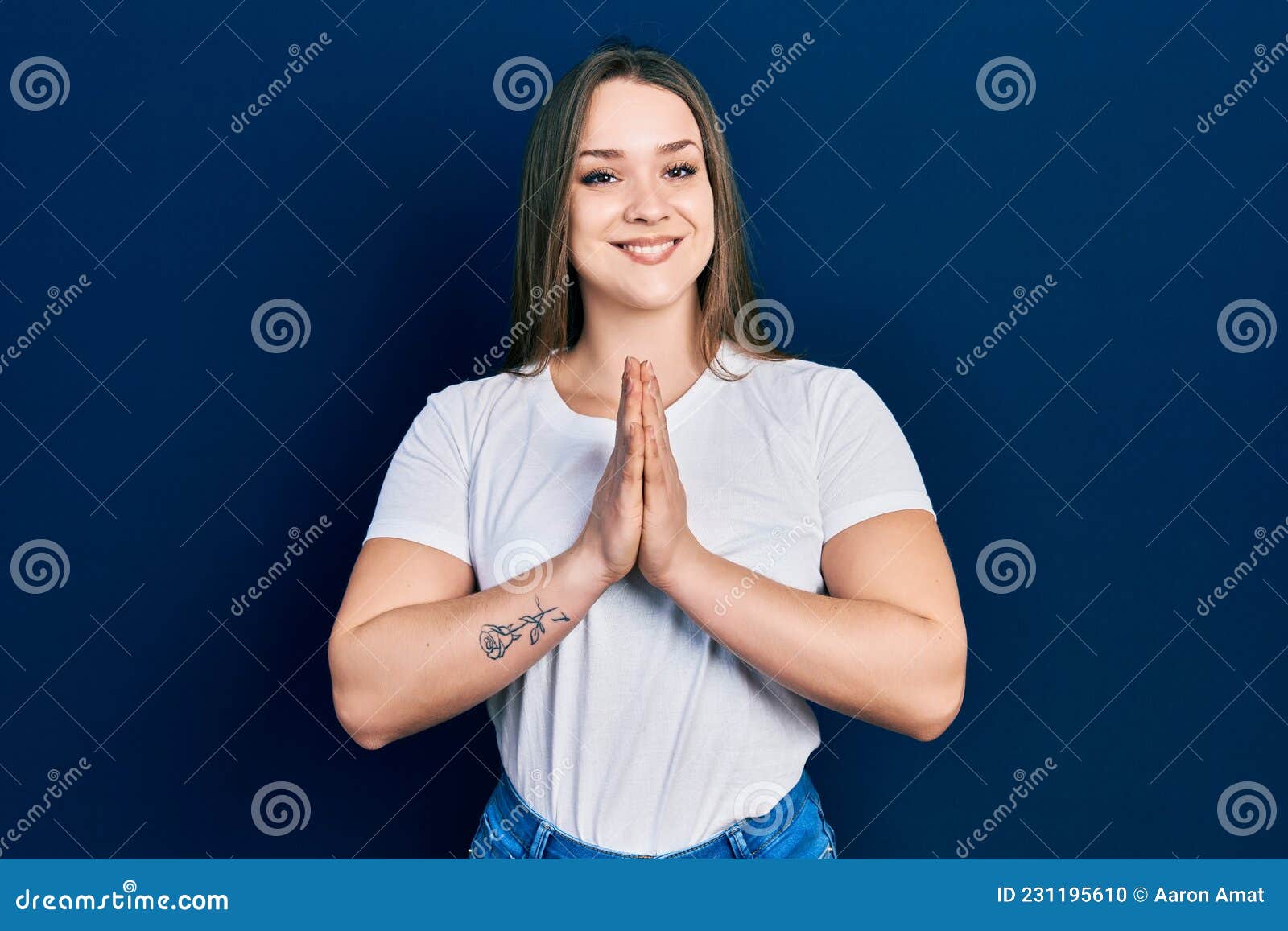 Young Hispanic Girl Wearing Casual White T Shirt Praying With Hands