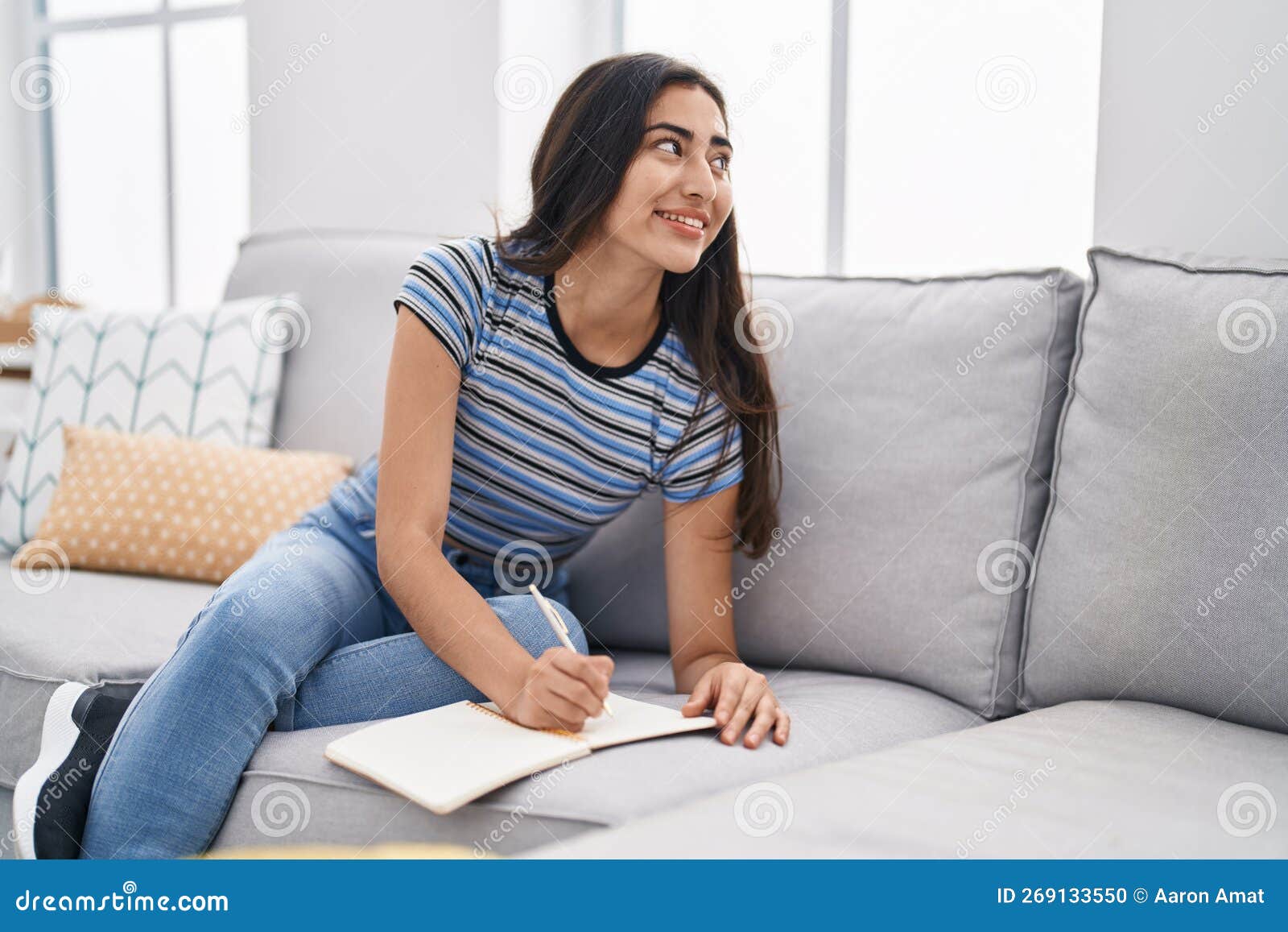 Young Hispanic Girl Writing on Notebook Sitting on Sofa at Home Stock ...